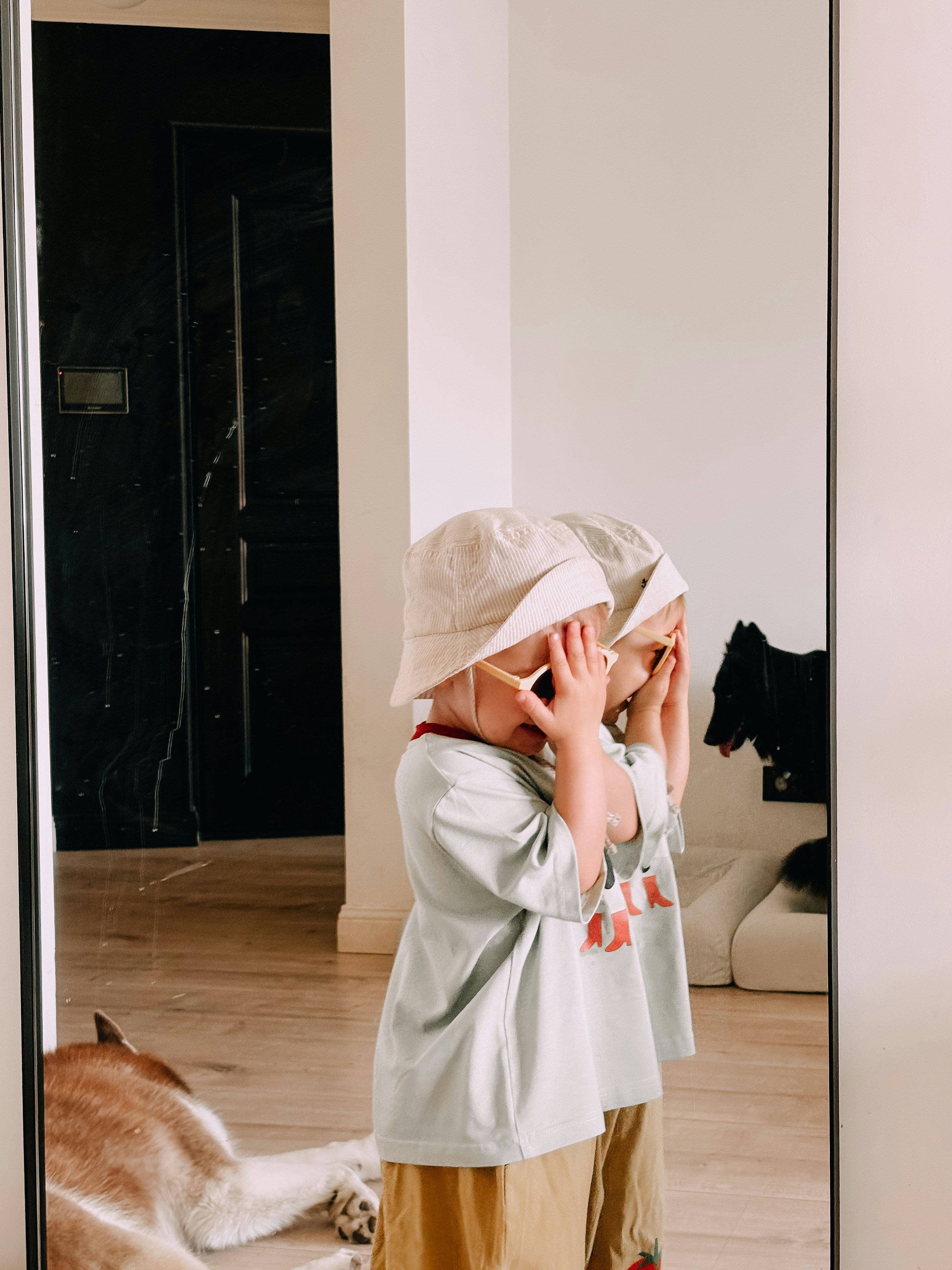 A toddler plays peek-a-boo with a mirror.