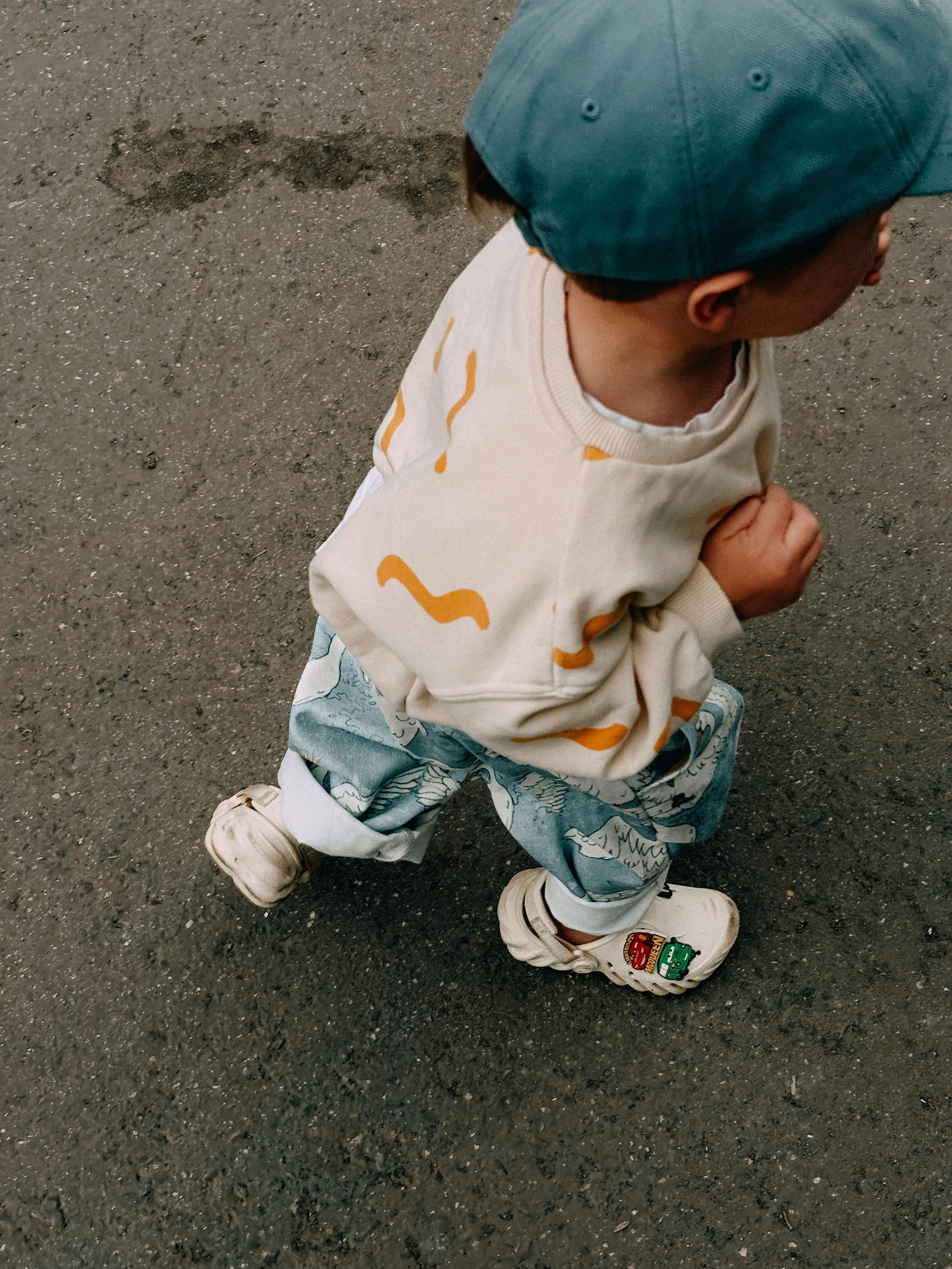 A small child is happily walking along the pavement.