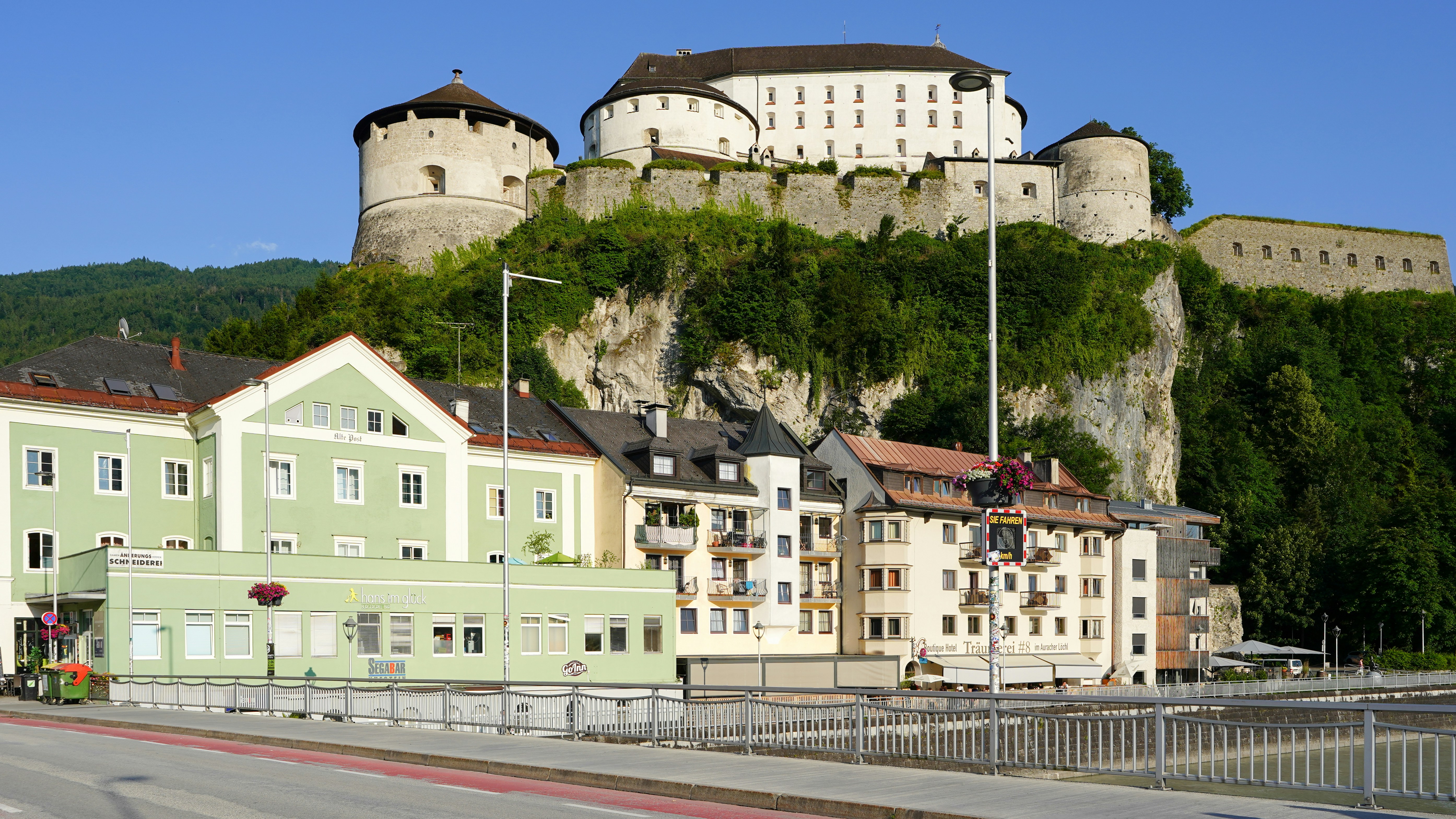 A castle stands atop a hill overlooking buildings.
