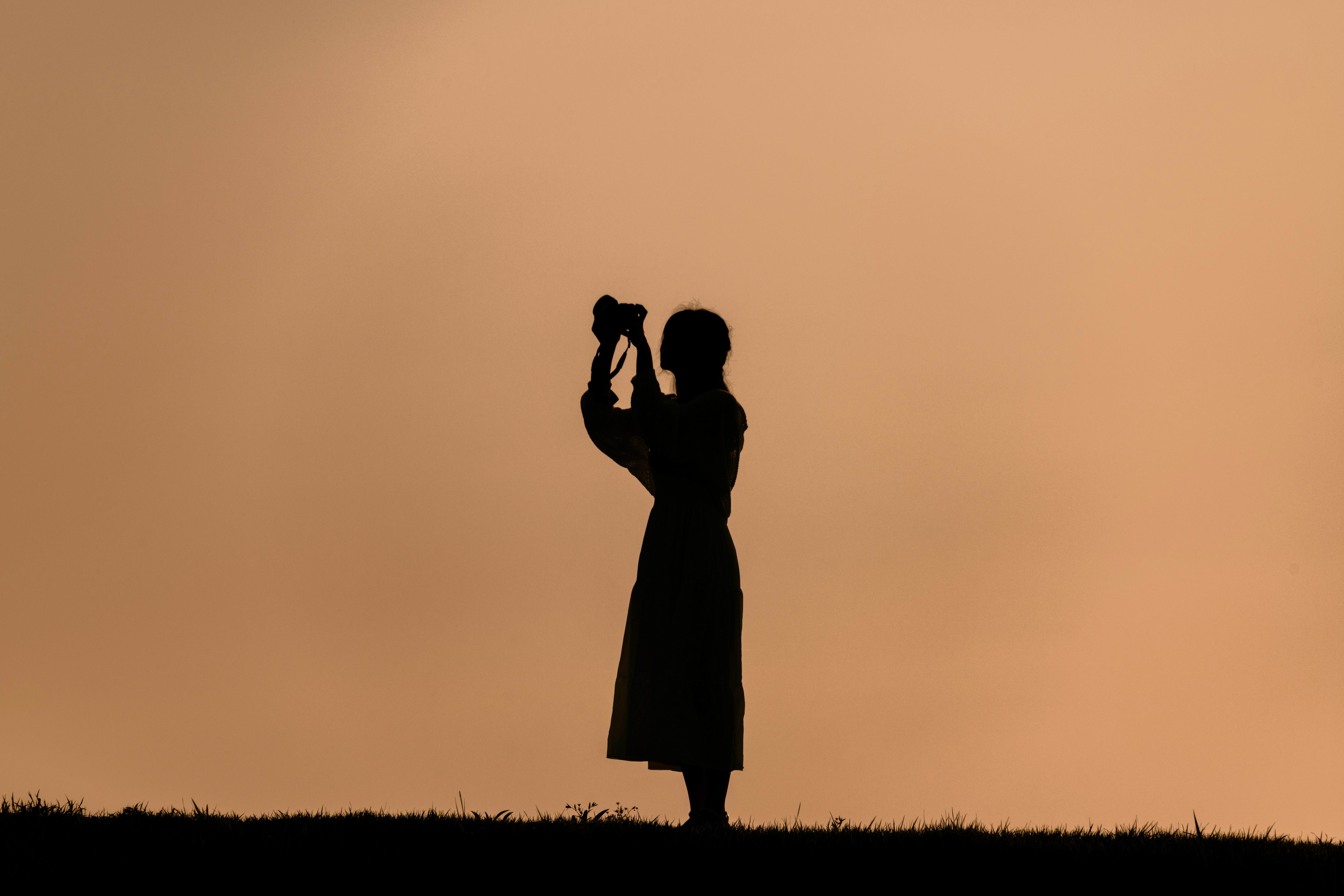 A photographer takes pictures silhouetted by the sun.