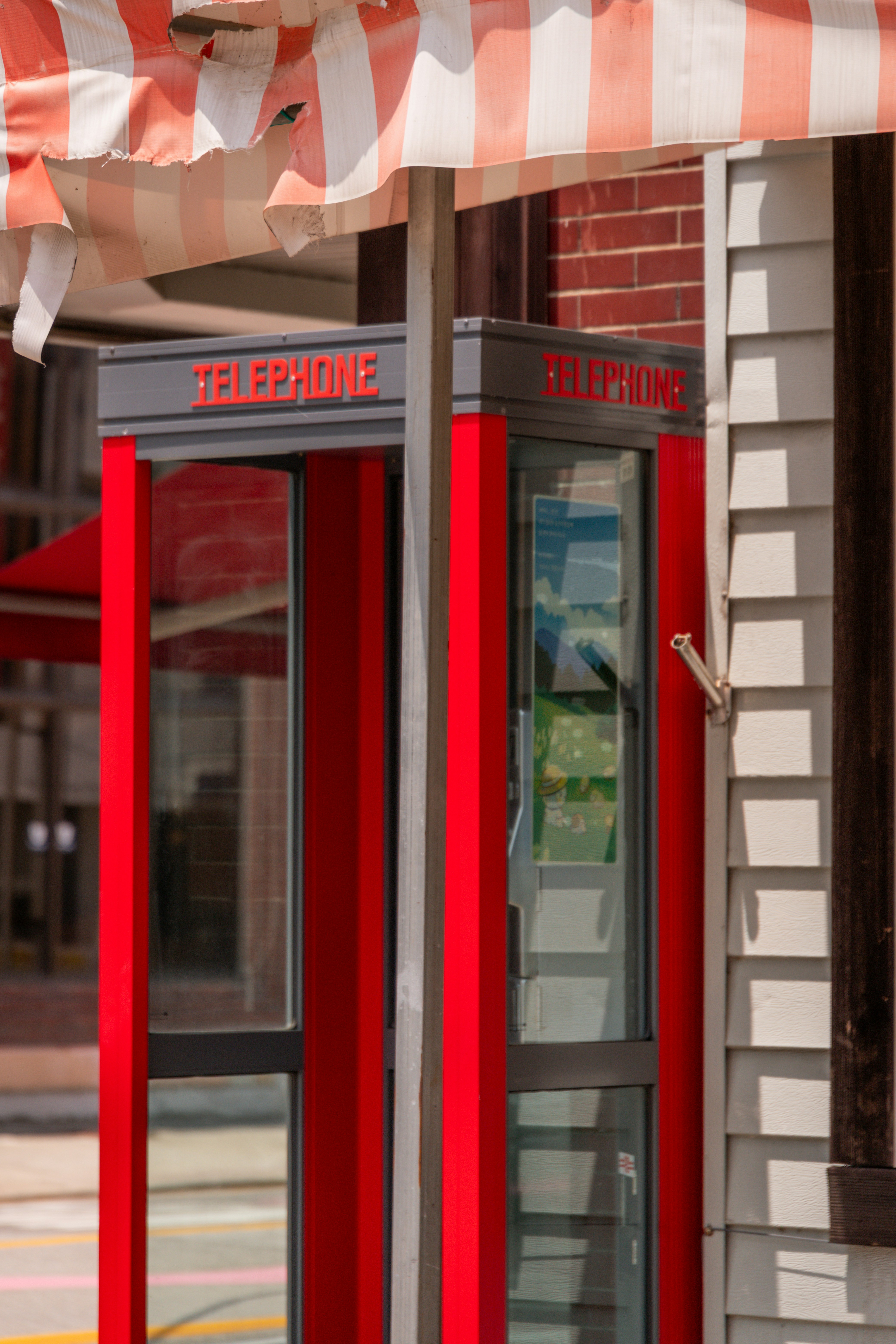 Crimson Telephone Booth Framed by a Striped Canopy