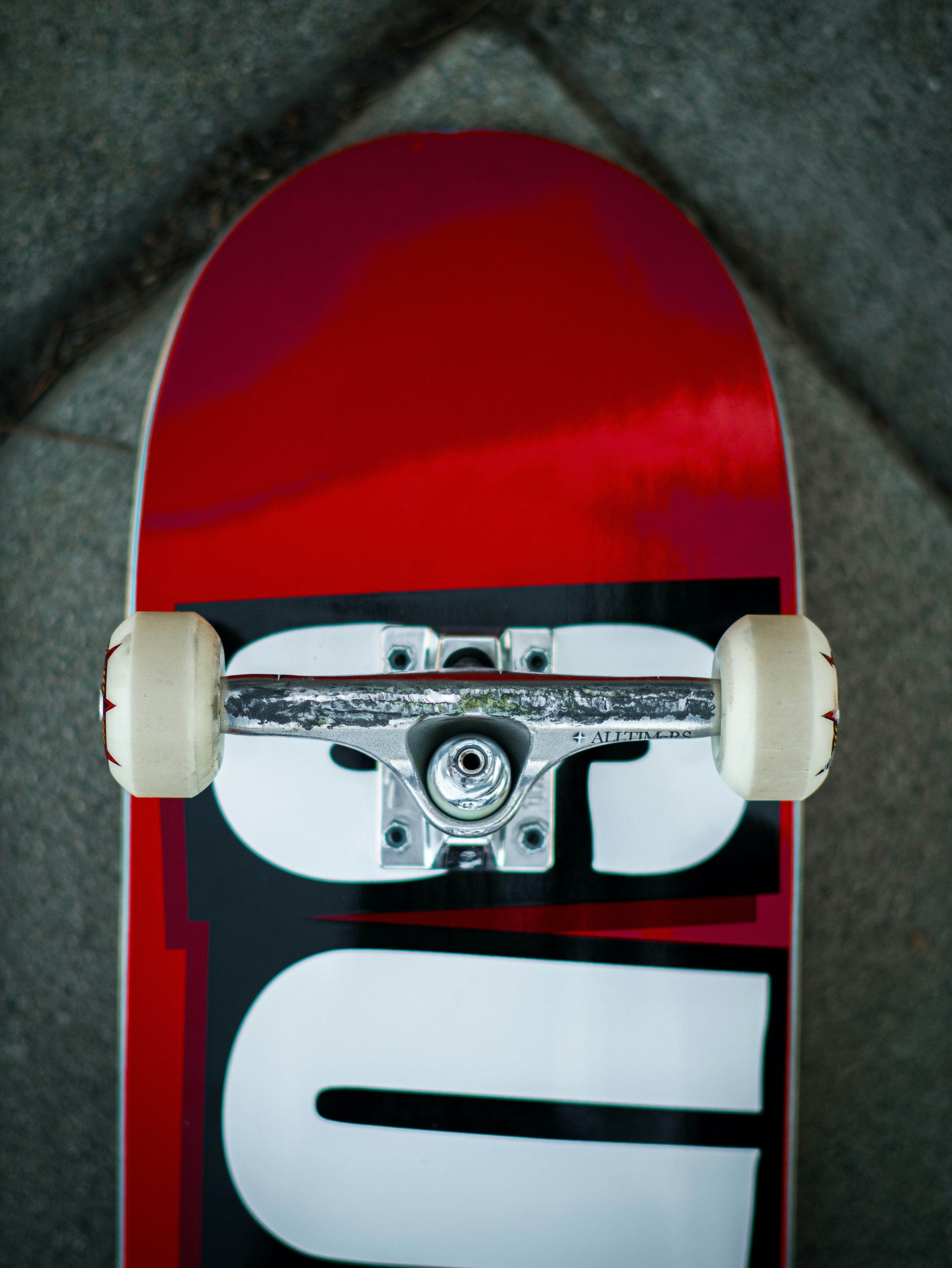 A red and white skateboard rests on concrete.