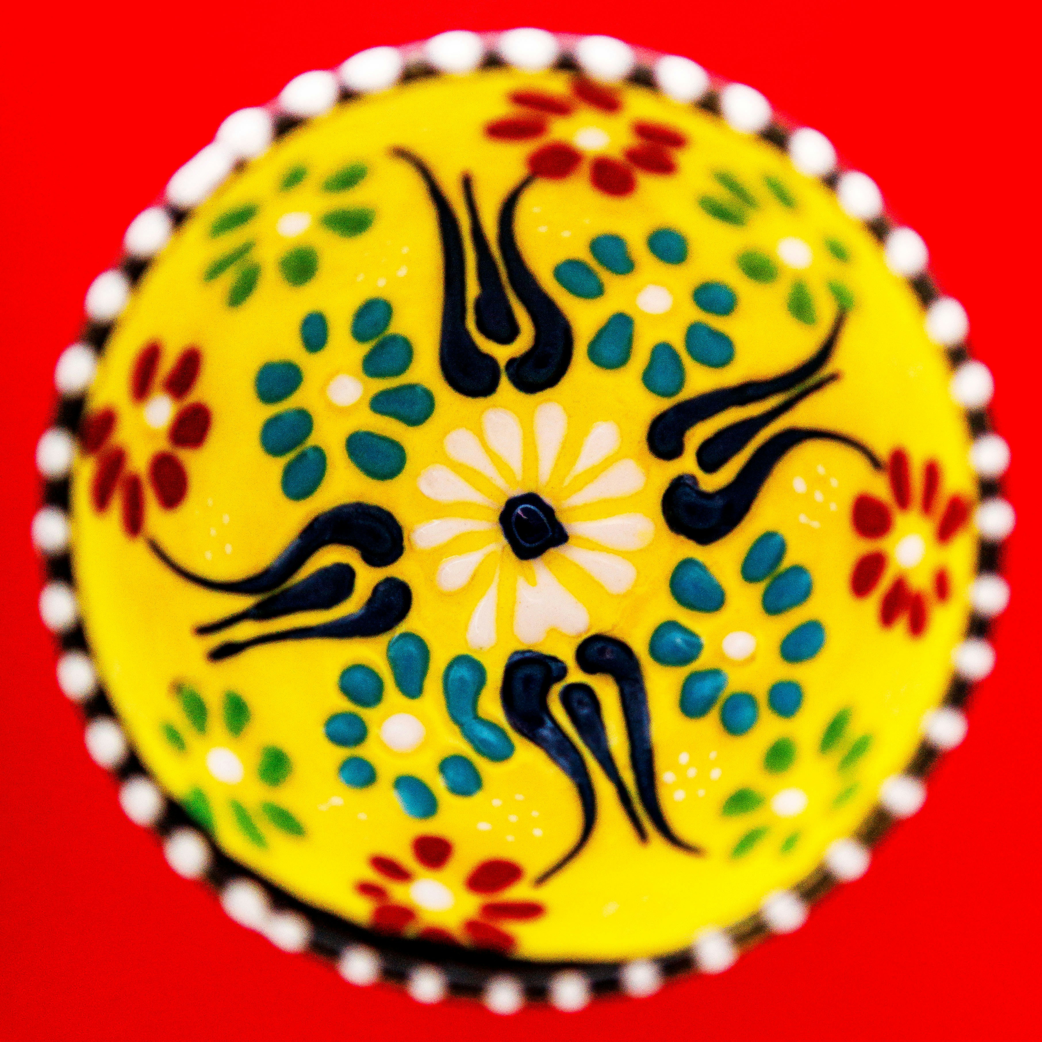 Colorful ceramic bowl adorned with intricate floral patterns, set against a vivid red background.