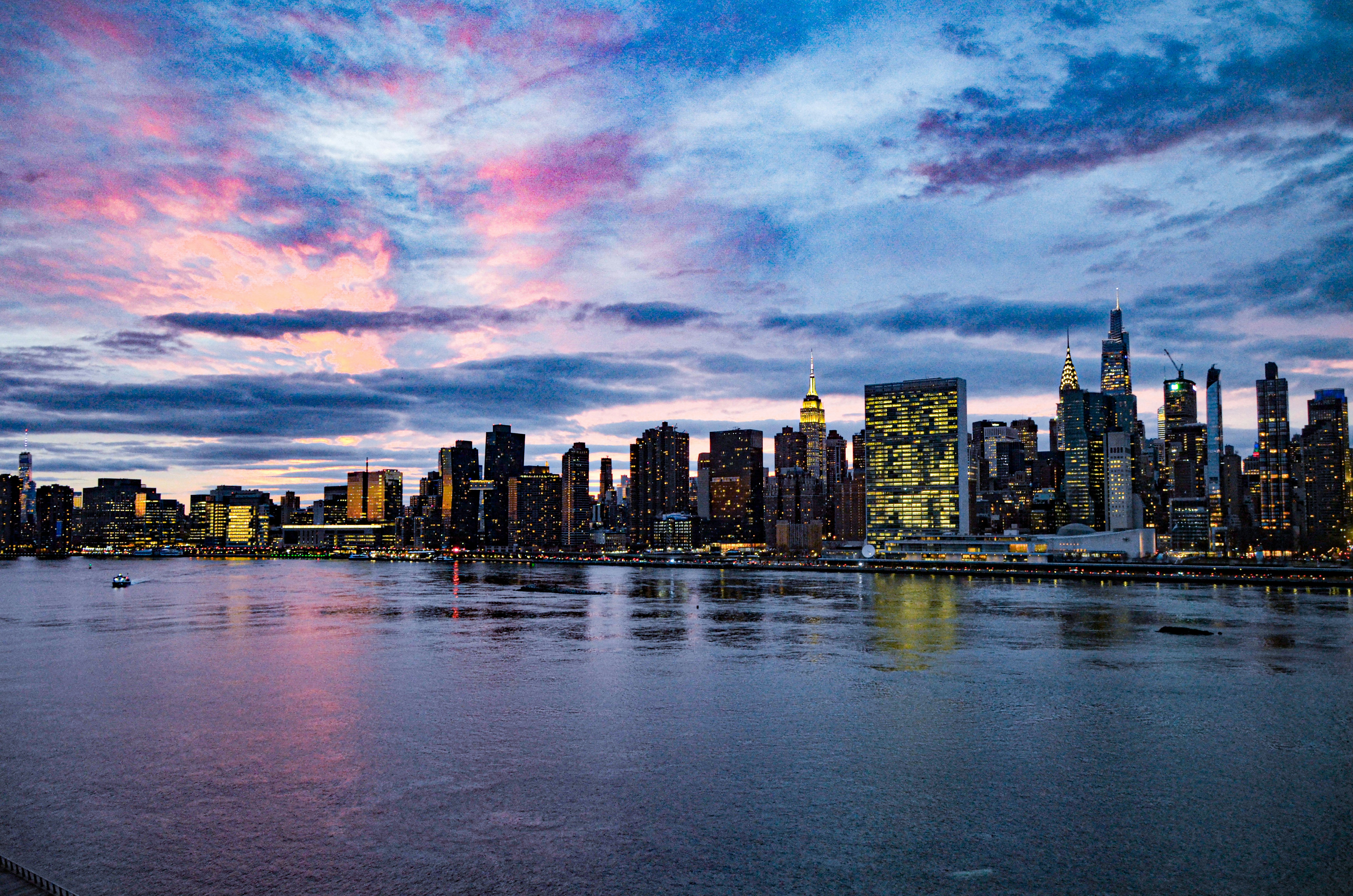 New york city skyline at dusk reflecting in water.