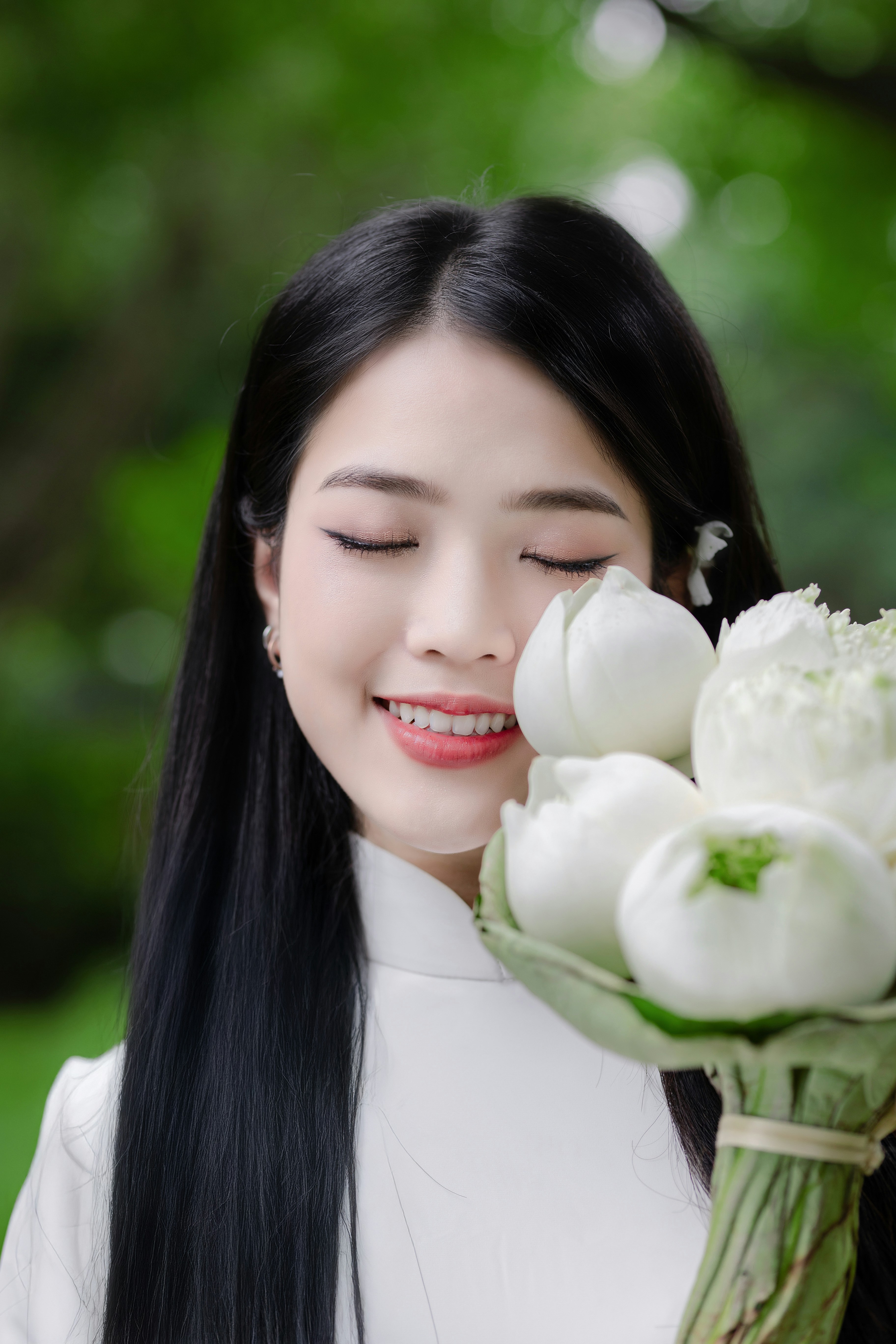 Vietnamese Ao Dai | Smiling woman with white flowers in her hands.