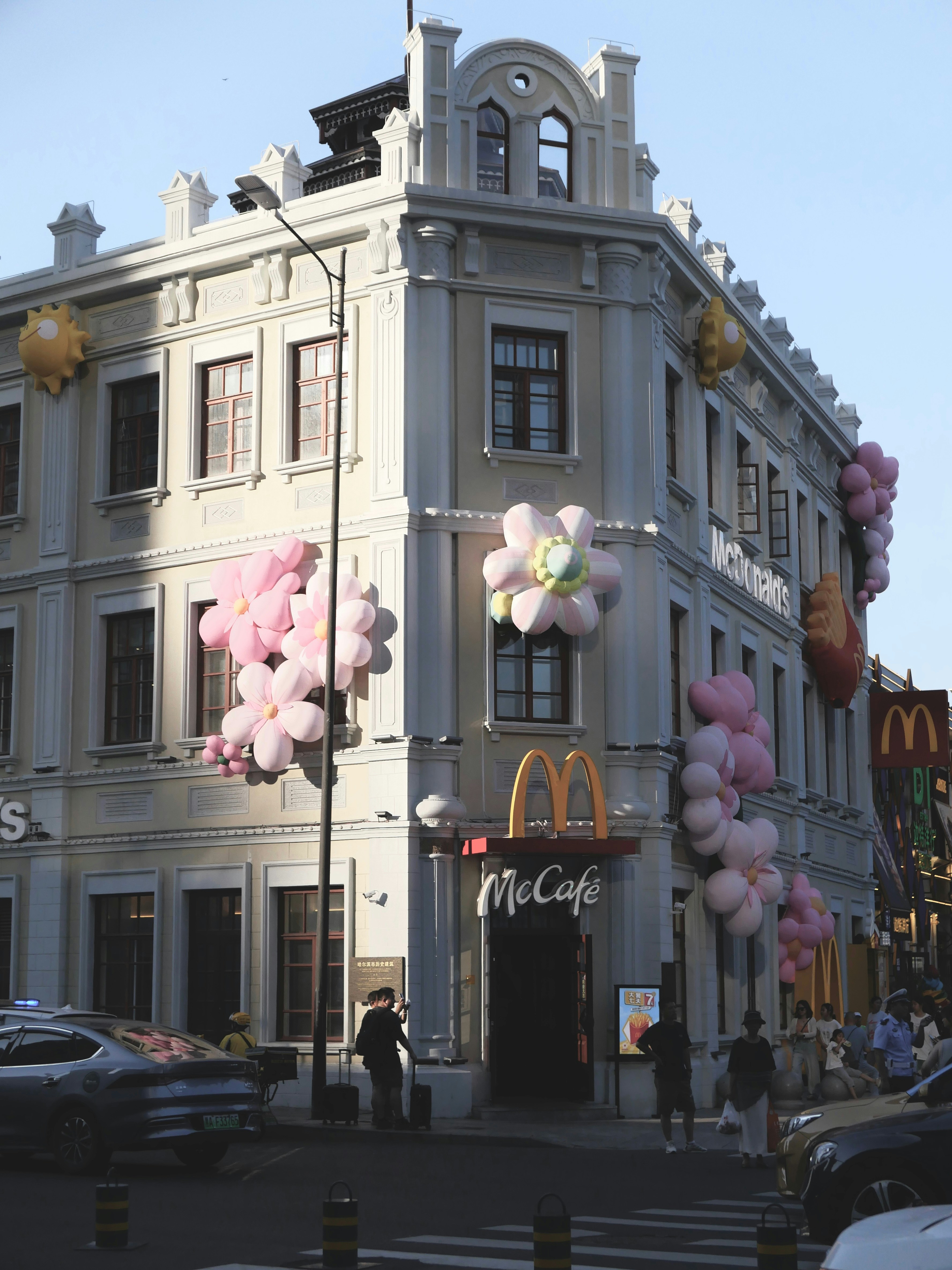 A McDonald's restaurant adorned with colorful balloons and floral decorations, showcasing a playful and inviting atmosphere. The unique architectural design adds charm to the festive display.