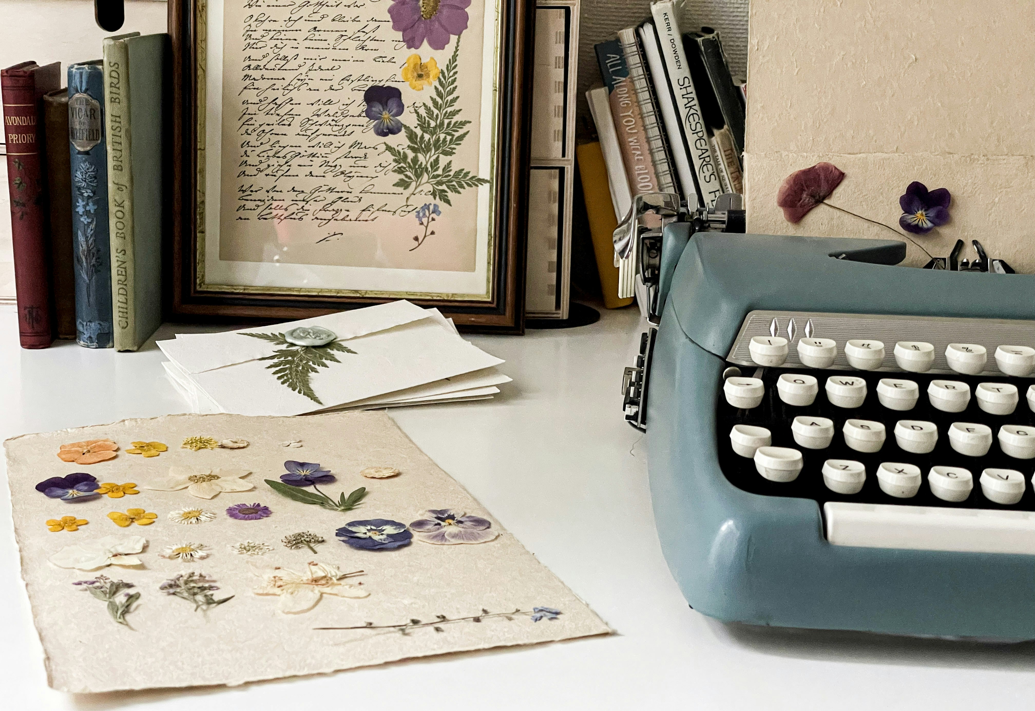 Pressed Botanicals Guard a Turquoise Typewriter on a Quiet Desk