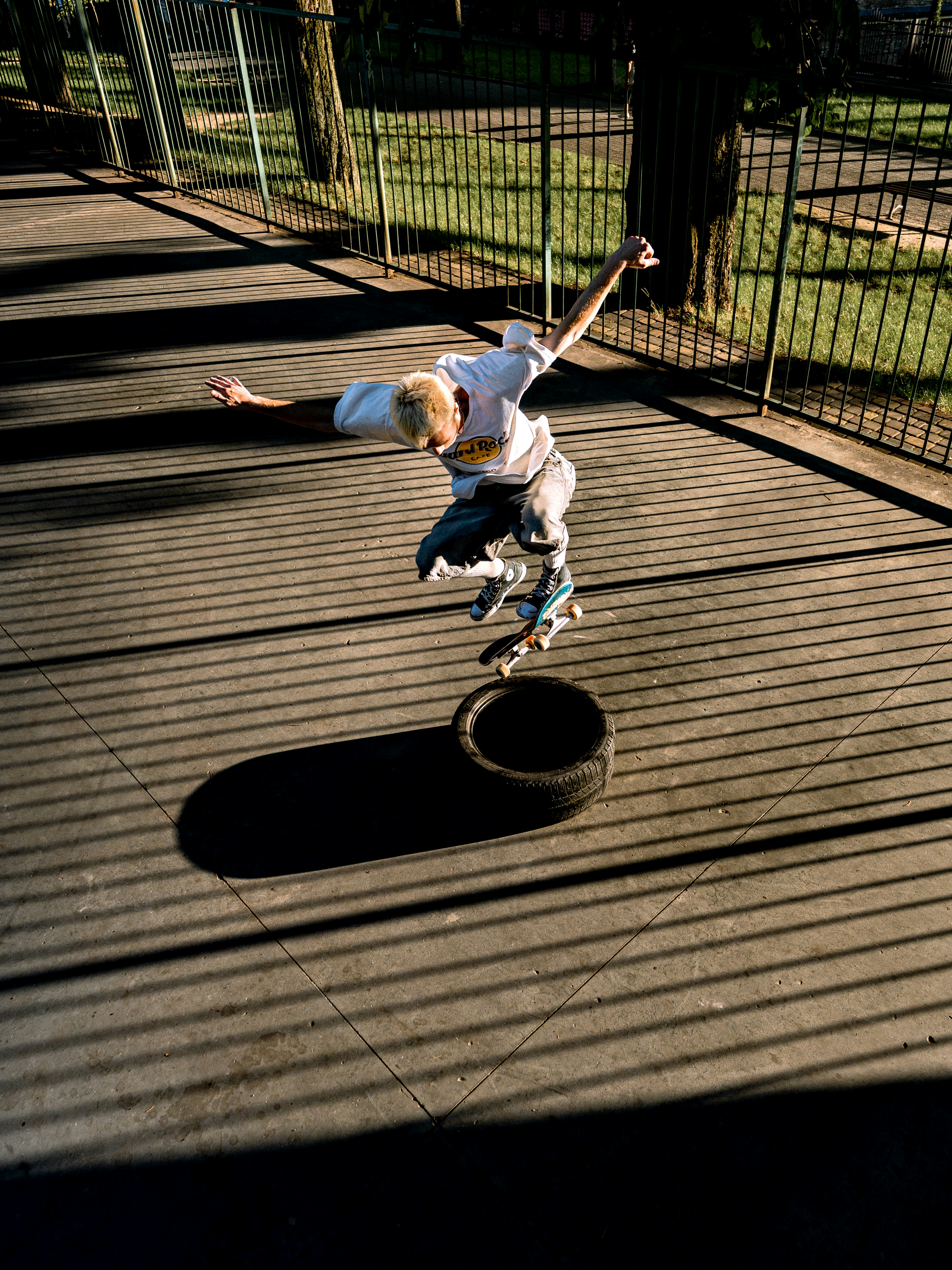 A skateboarder jumps over a tire in mid-air.