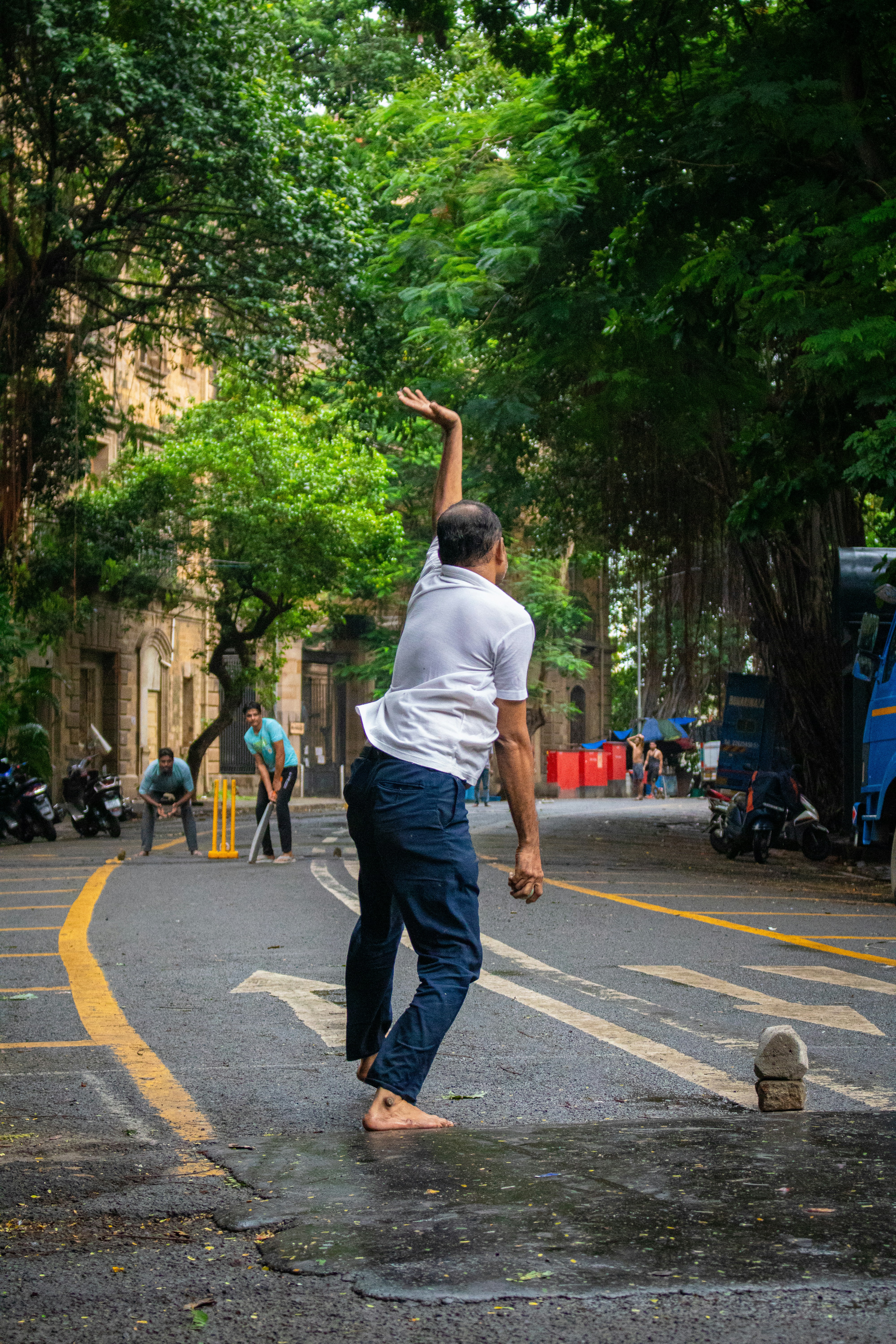 People play street cricket (gully cricket) on the streets of Ballard Estate, Fort, Mumbai on a Sunday afternoon.
