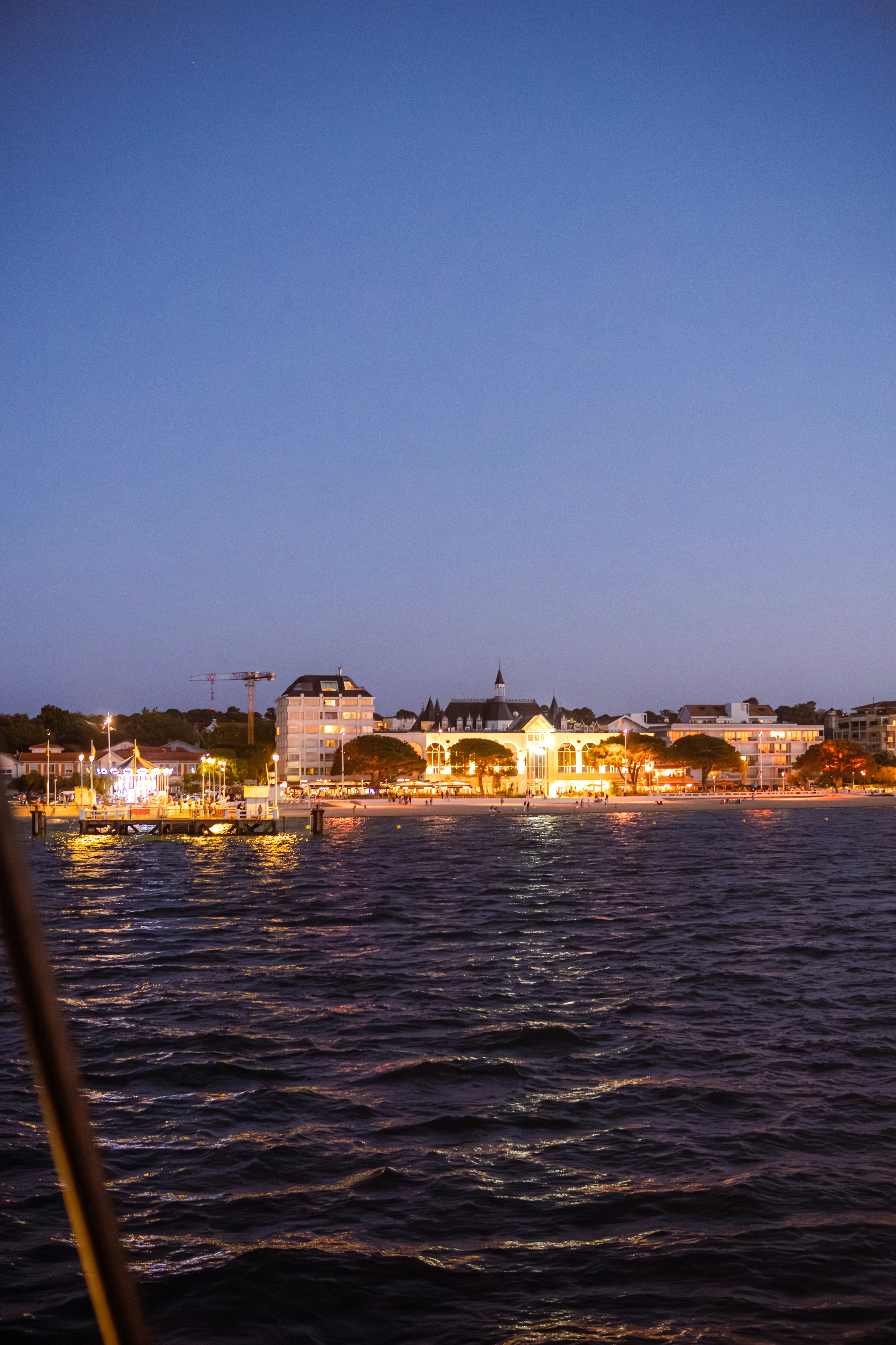 Looking out over Arcachon from the yacht | City lights shine on the water at dusk.