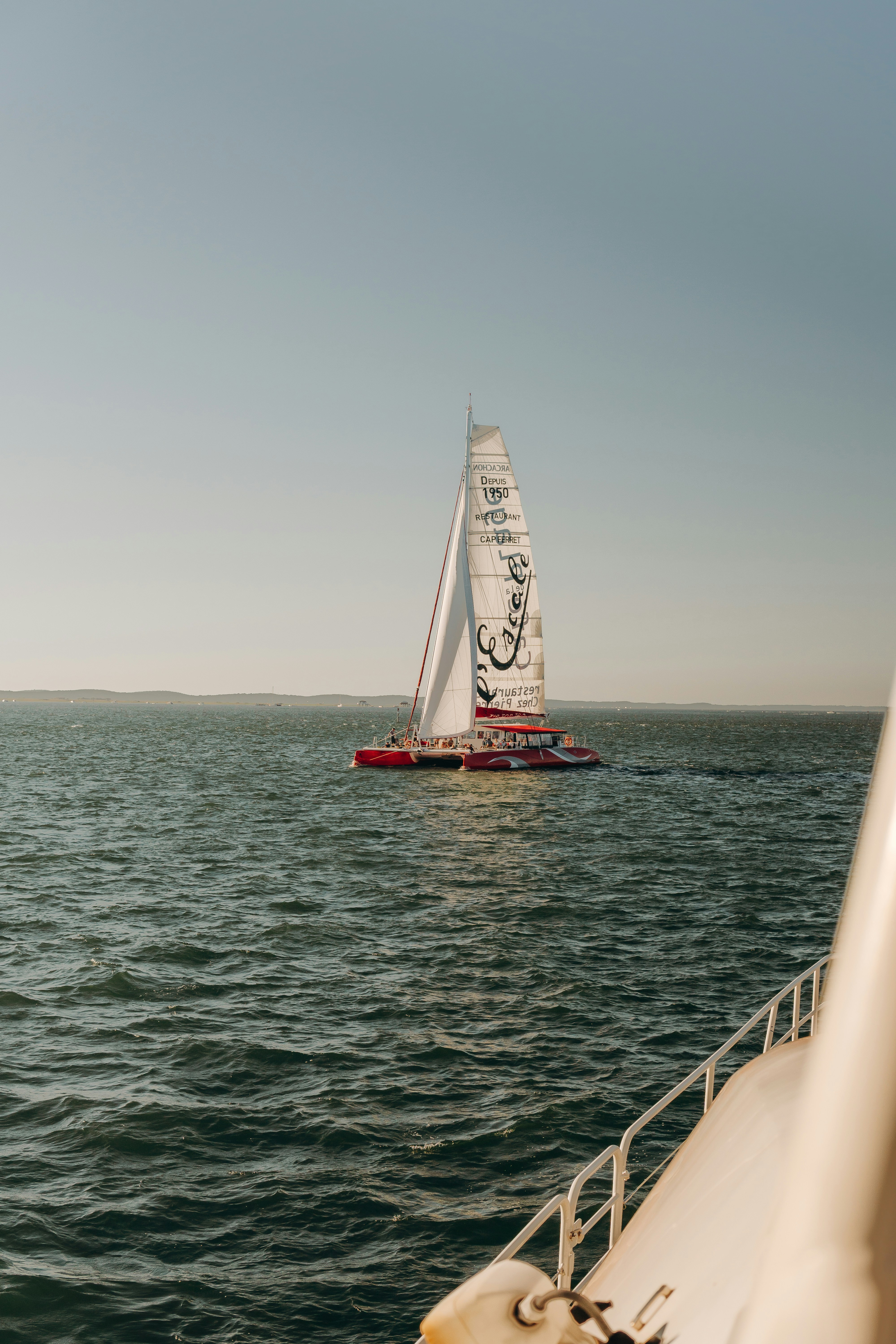 A sailboat navigates calm waters on a sunny day.