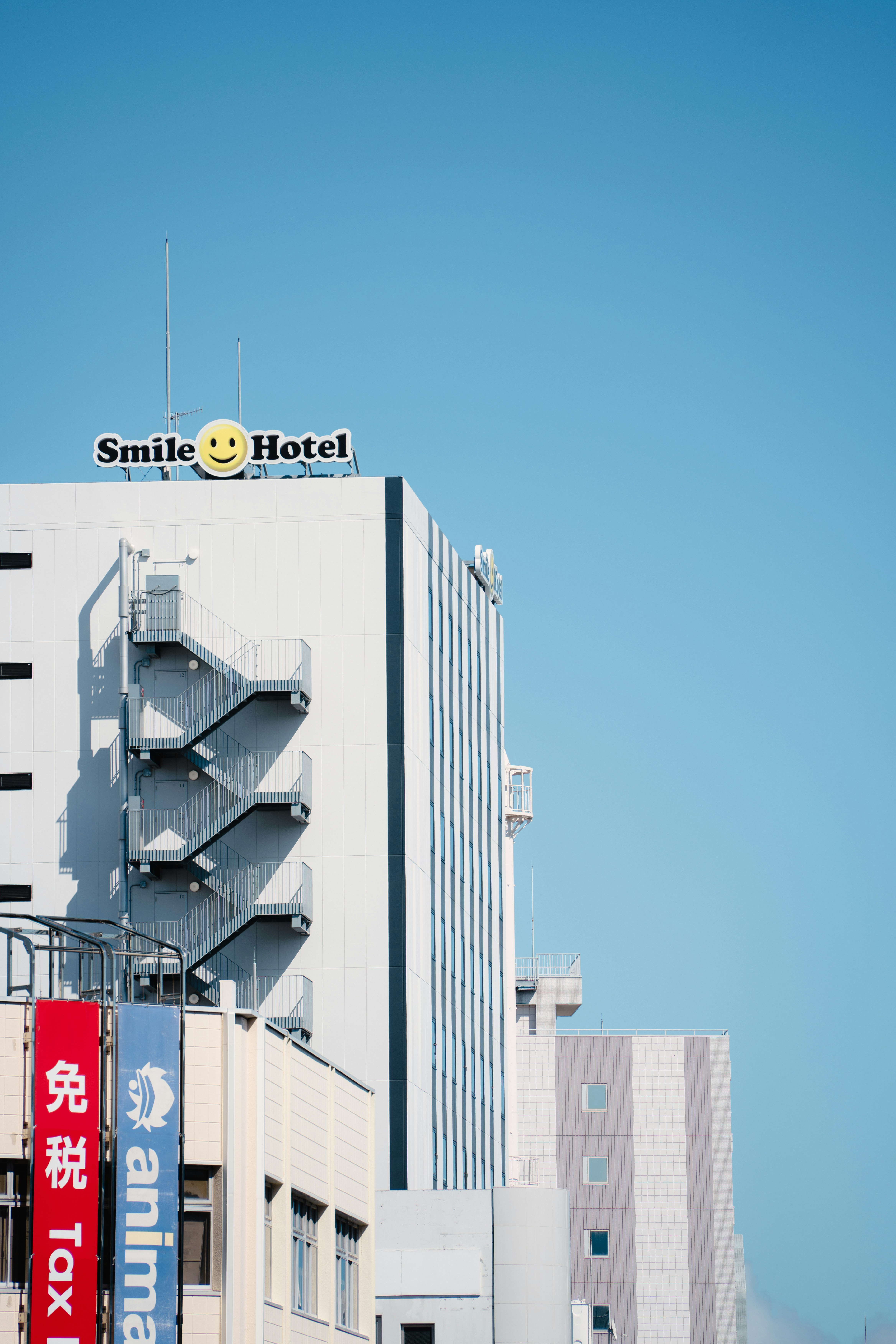 Smile hotel sign tops a building against a blue sky.