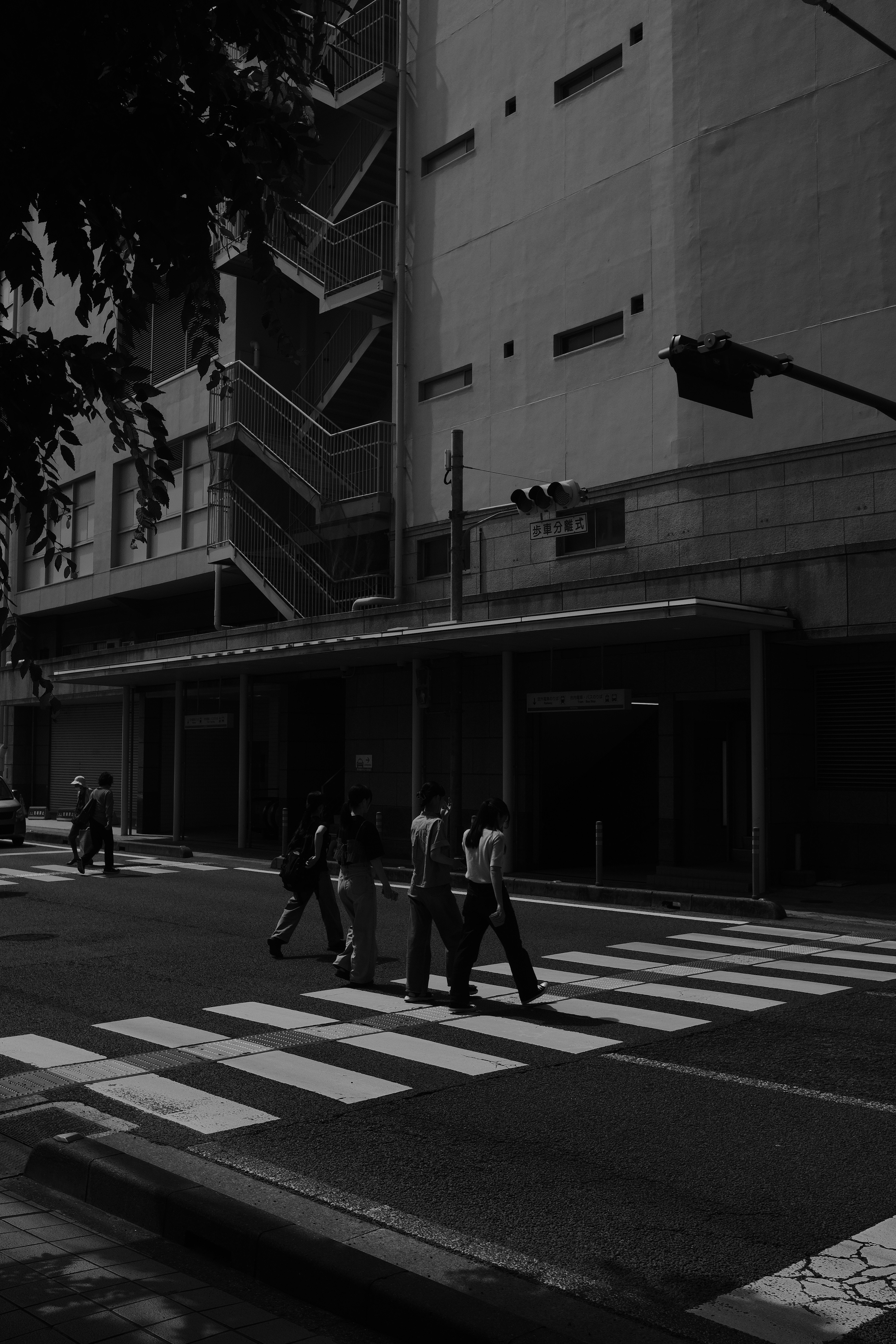 People cross a street in front of a building.