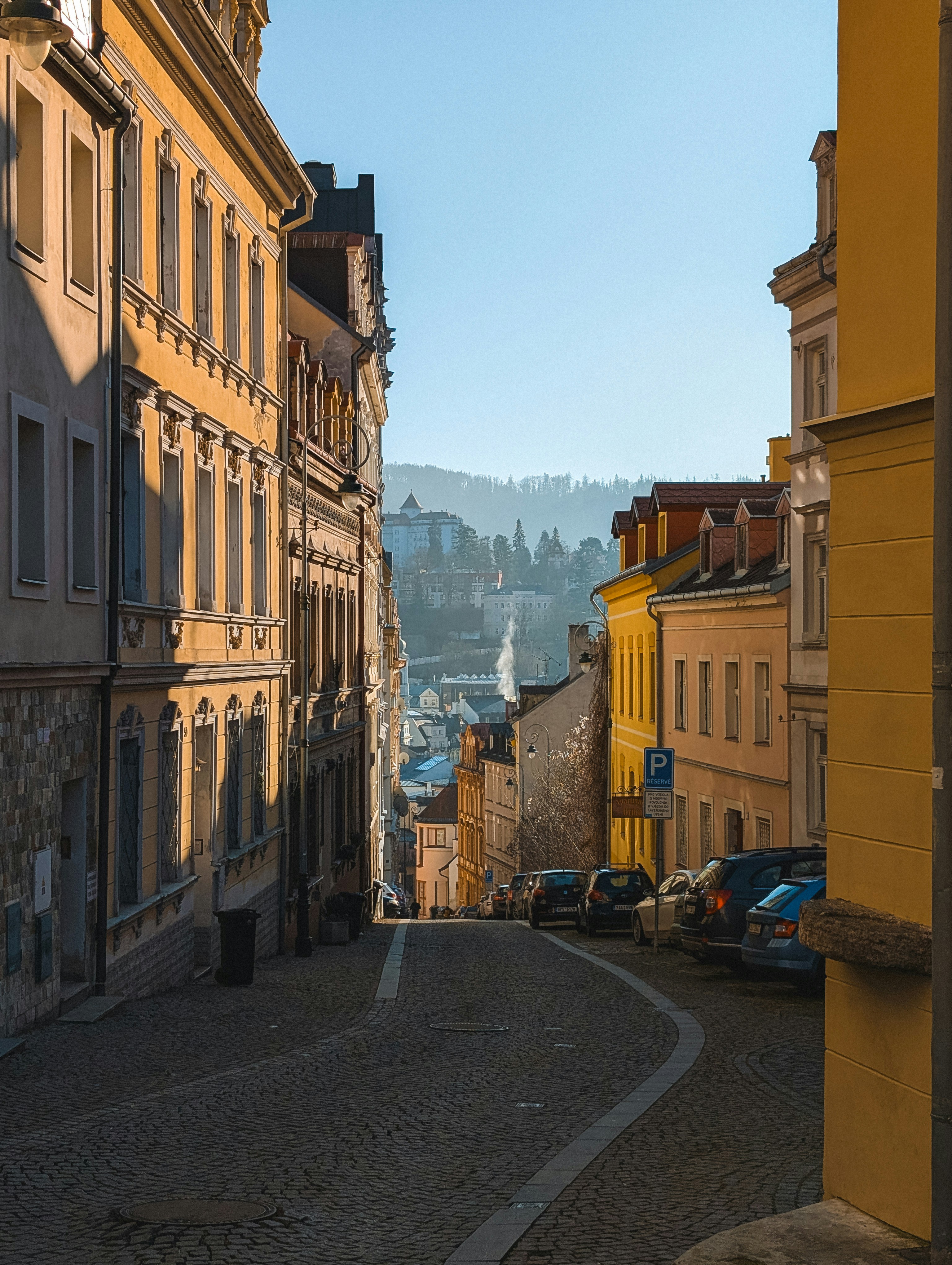 Morning Light on a Narrow Street in Karlovy Vary | A winding street runs between yellow buildings.