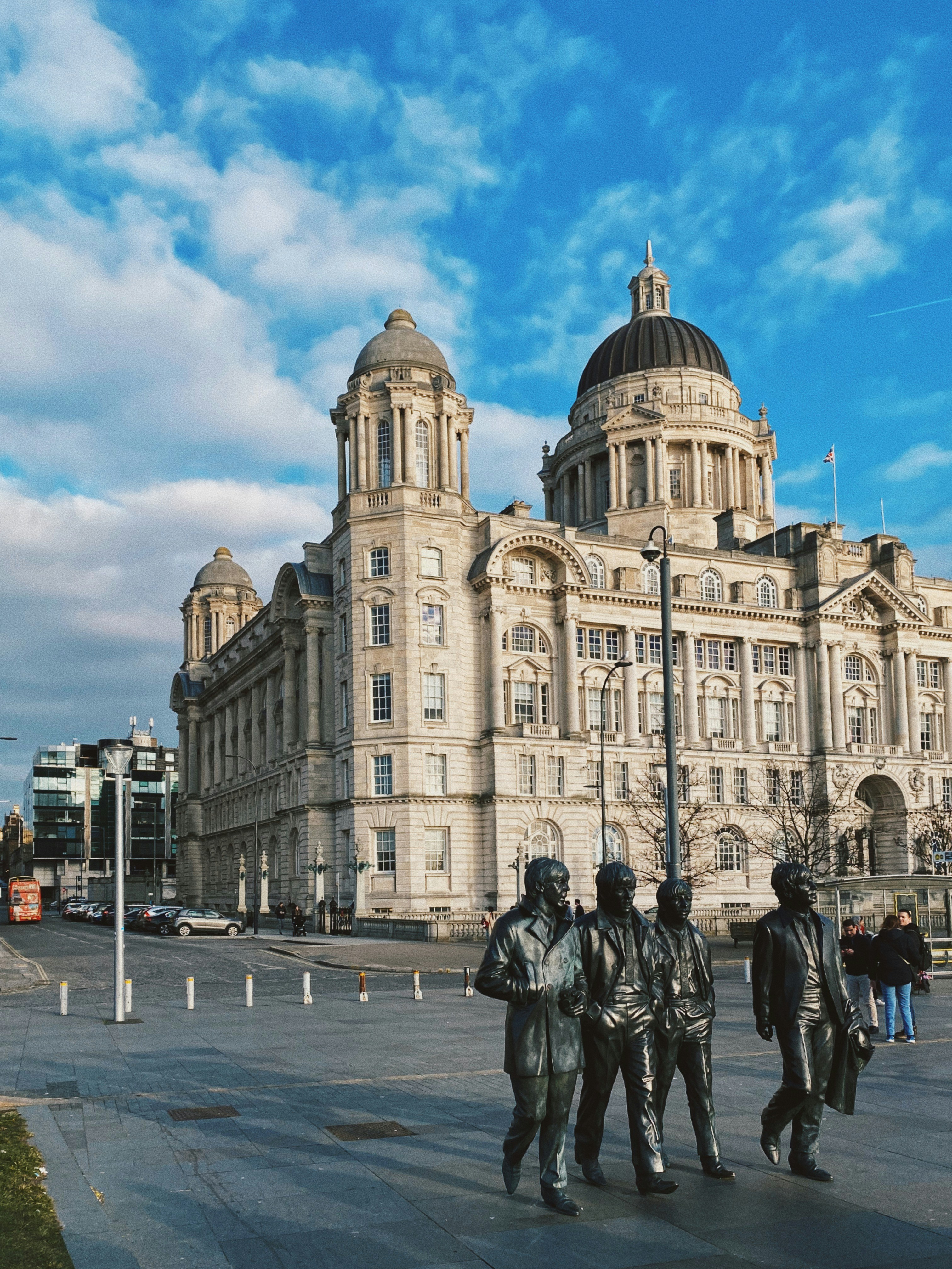 The beatles statue stands before a grand building.