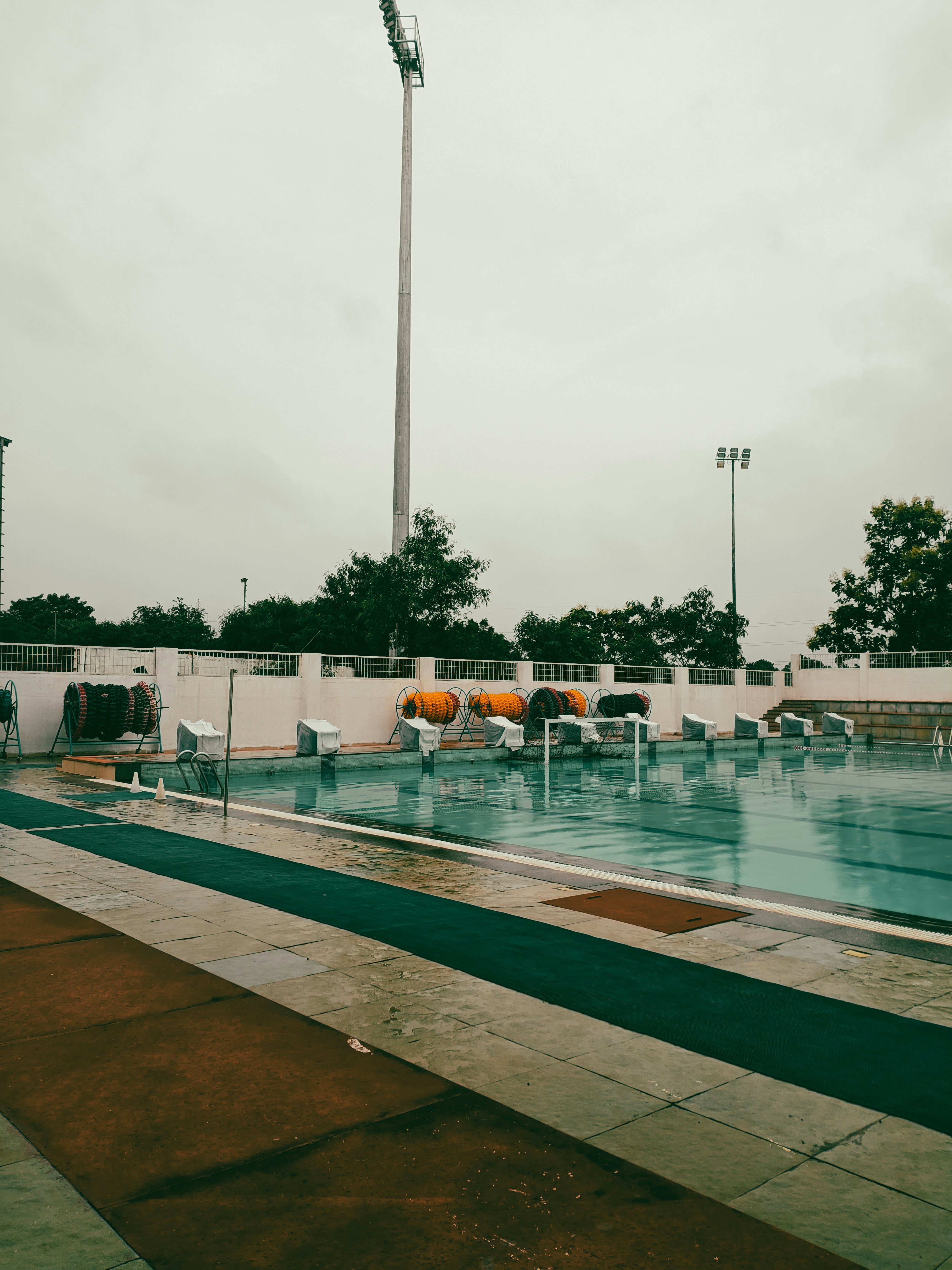 Moody pool scene with dramatic lighting. | An empty swimming pool on a cloudy day.