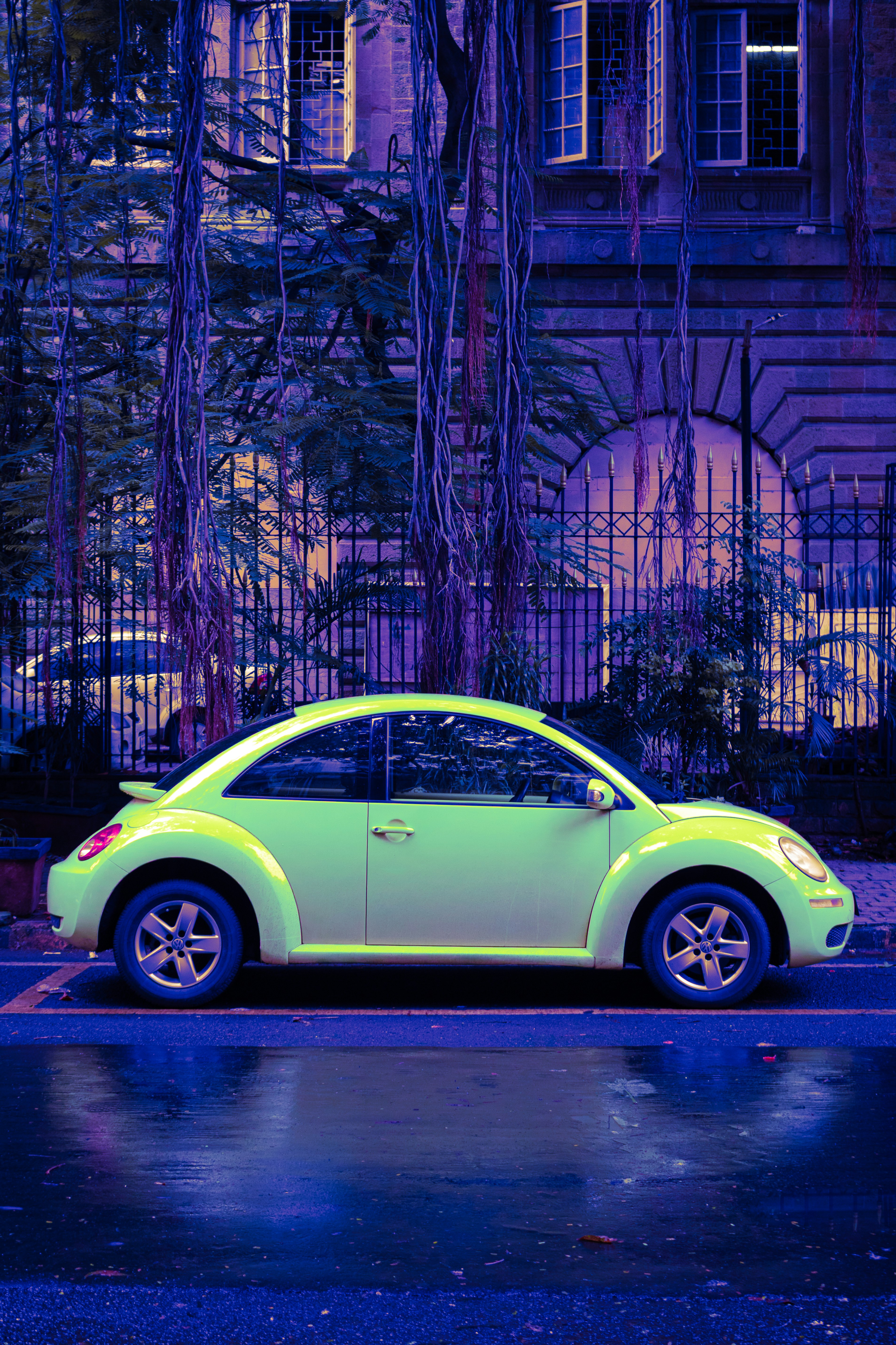 Photograph of a modern Volkwagen New Beetle parked on the street at Ballard Estate, Mumbai, India. | A bright green car parked in front of a building.