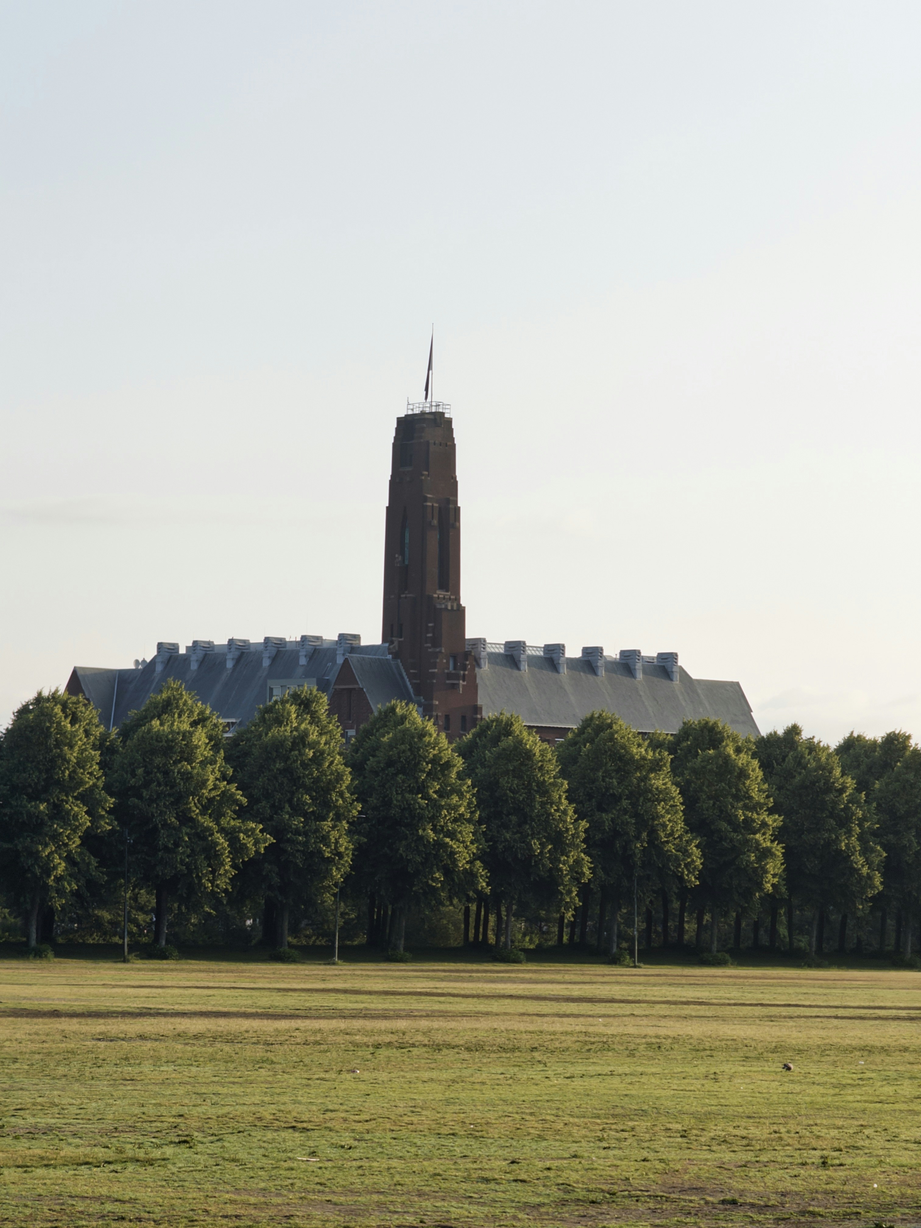 A tall building towers over a grassy field.