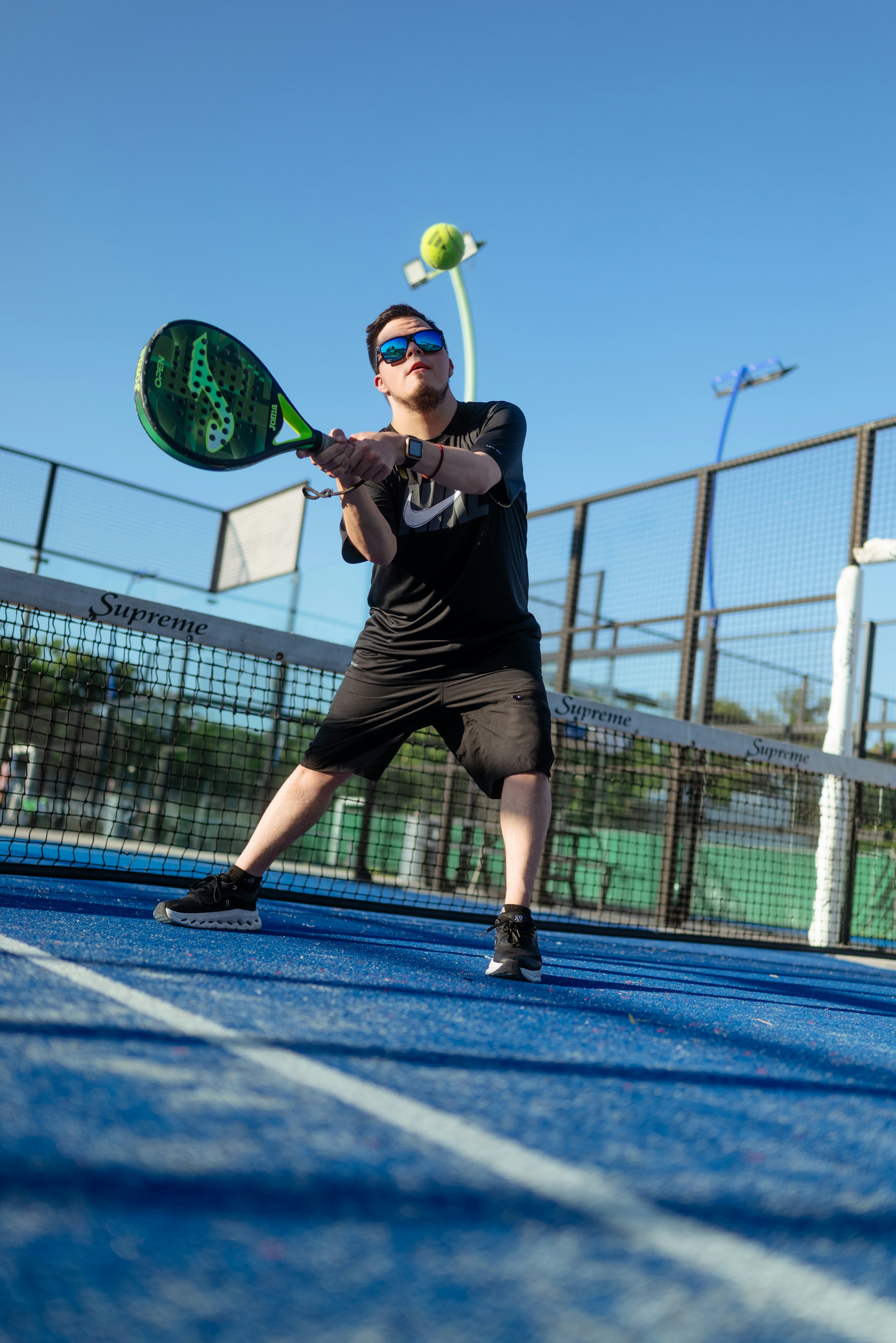 Athlete poised to strike a ball on a vibrant blue paddle court, showcasing focus and athleticism.