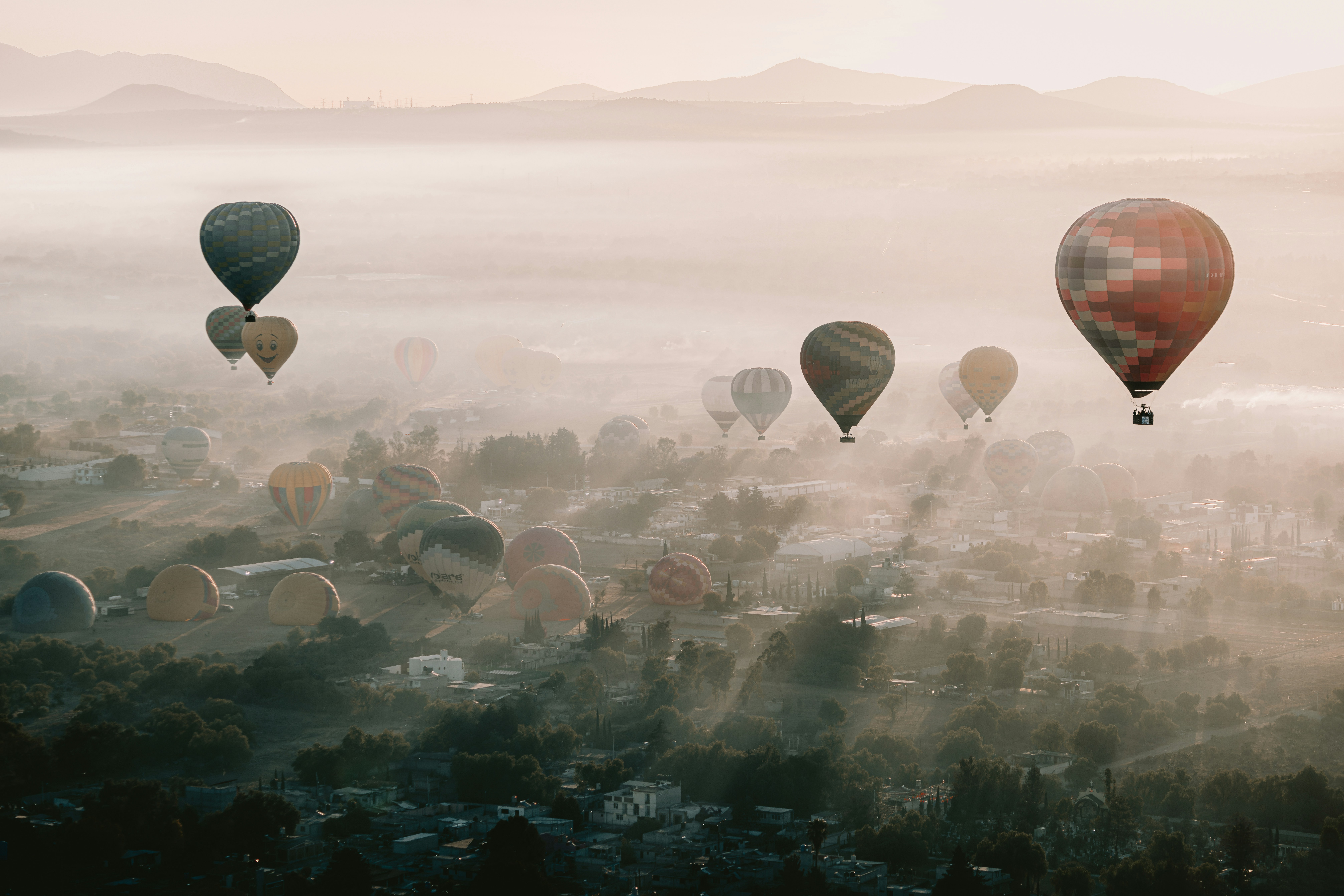 Hot air balloons fly above a misty landscape.