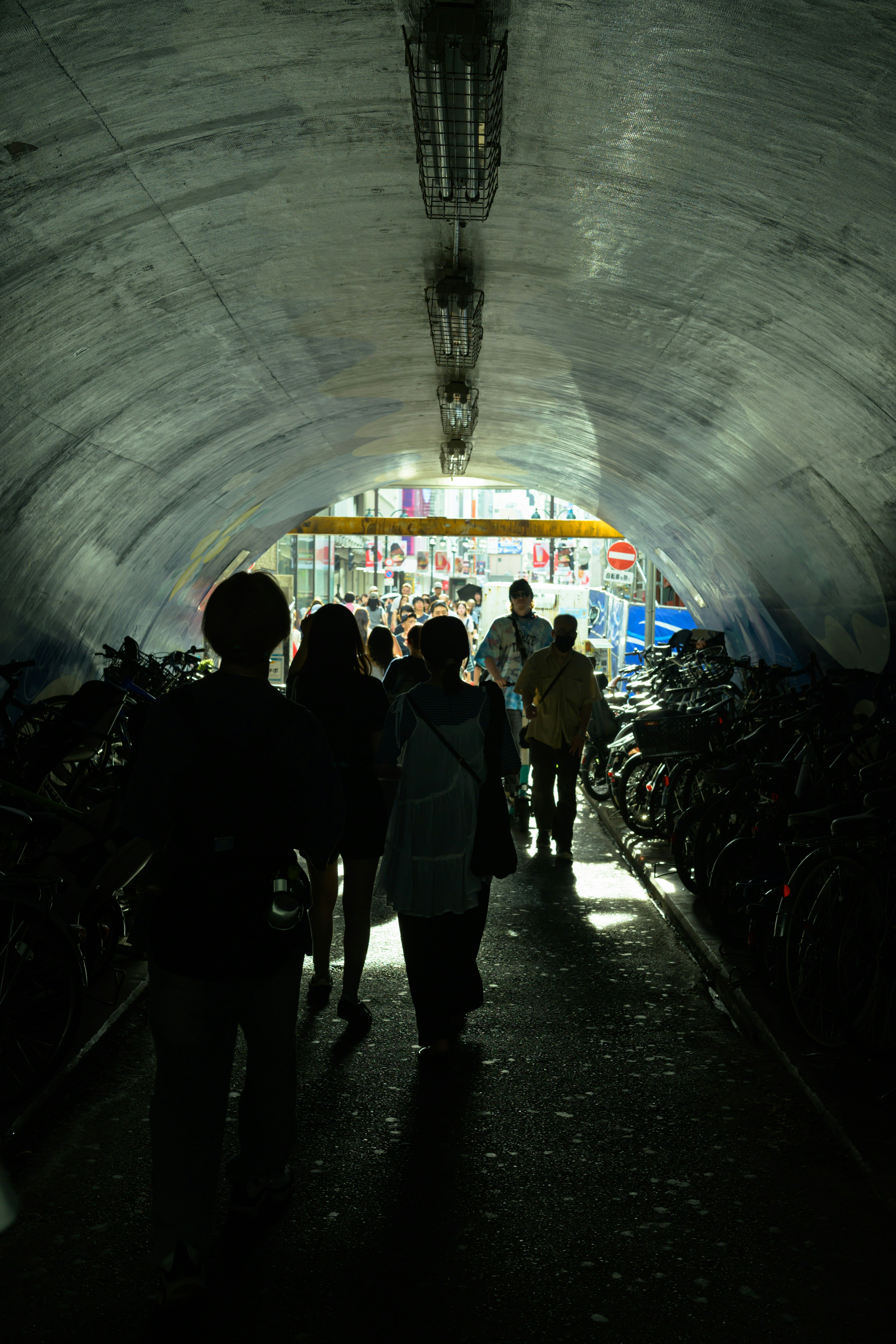 People walk through a tunnel towards bright light.
