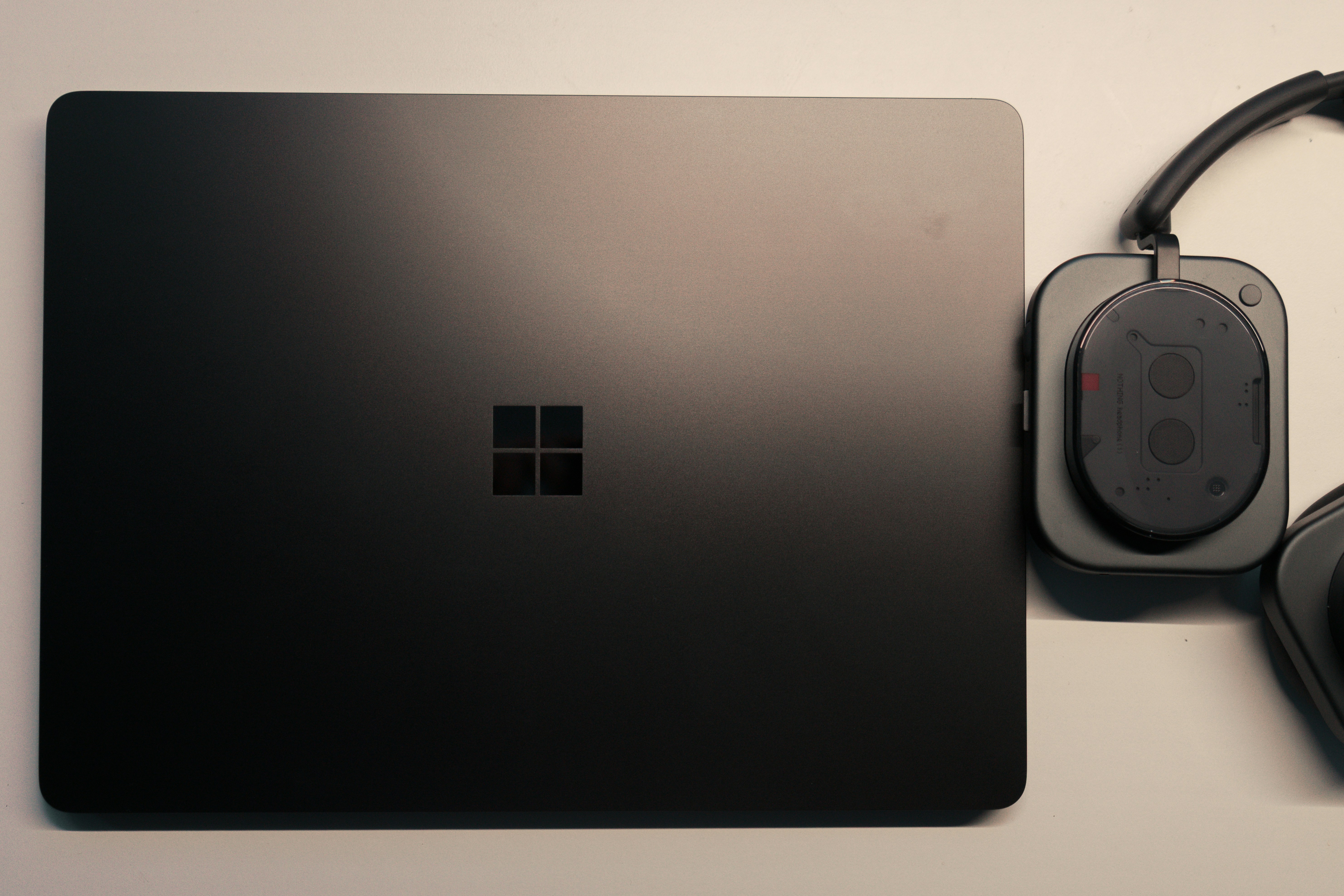 Nothing Headphones with Surface Laptop | A closed laptop computer with a charger.