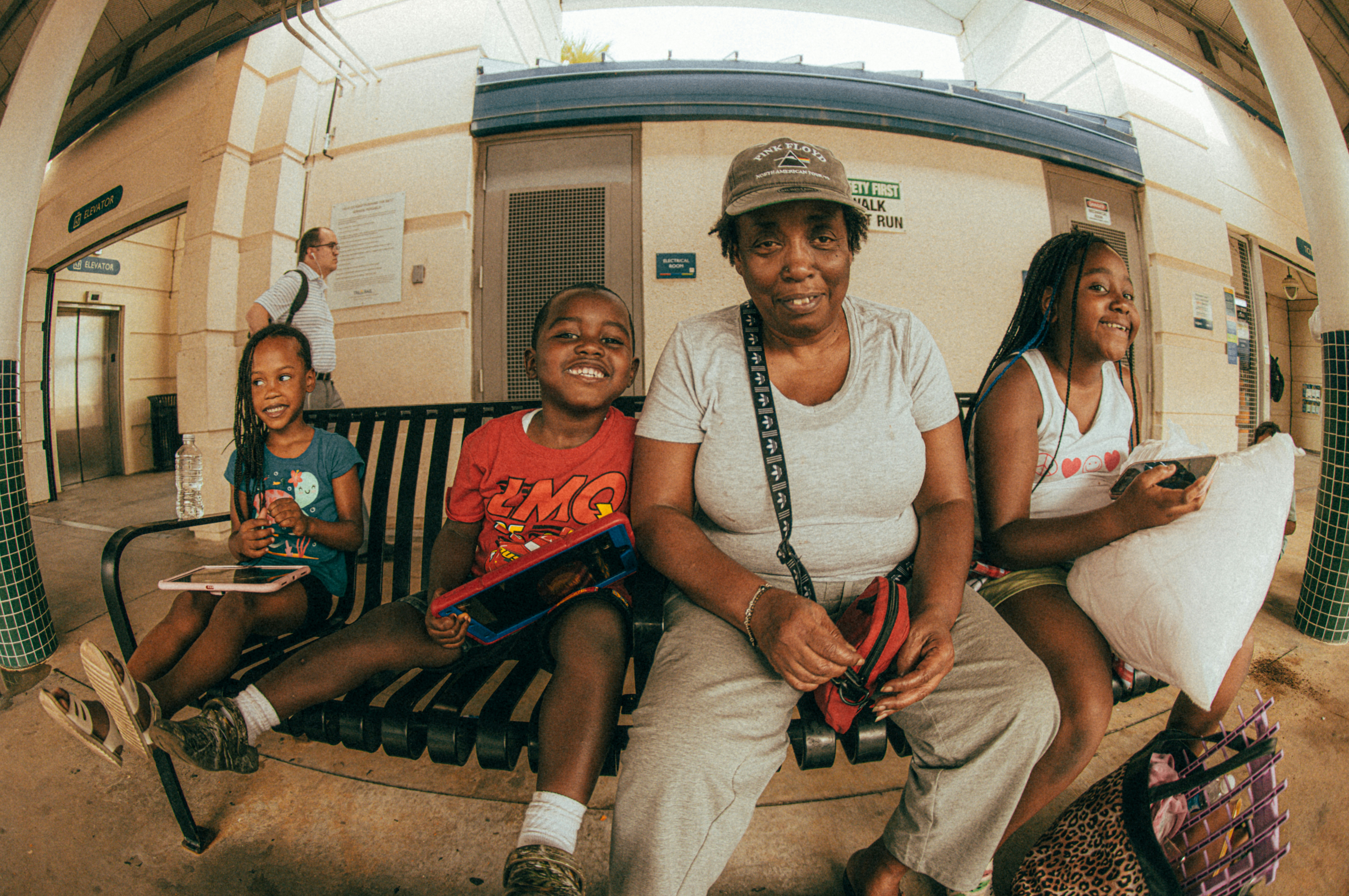 A grandma and three kids sit on a bench.