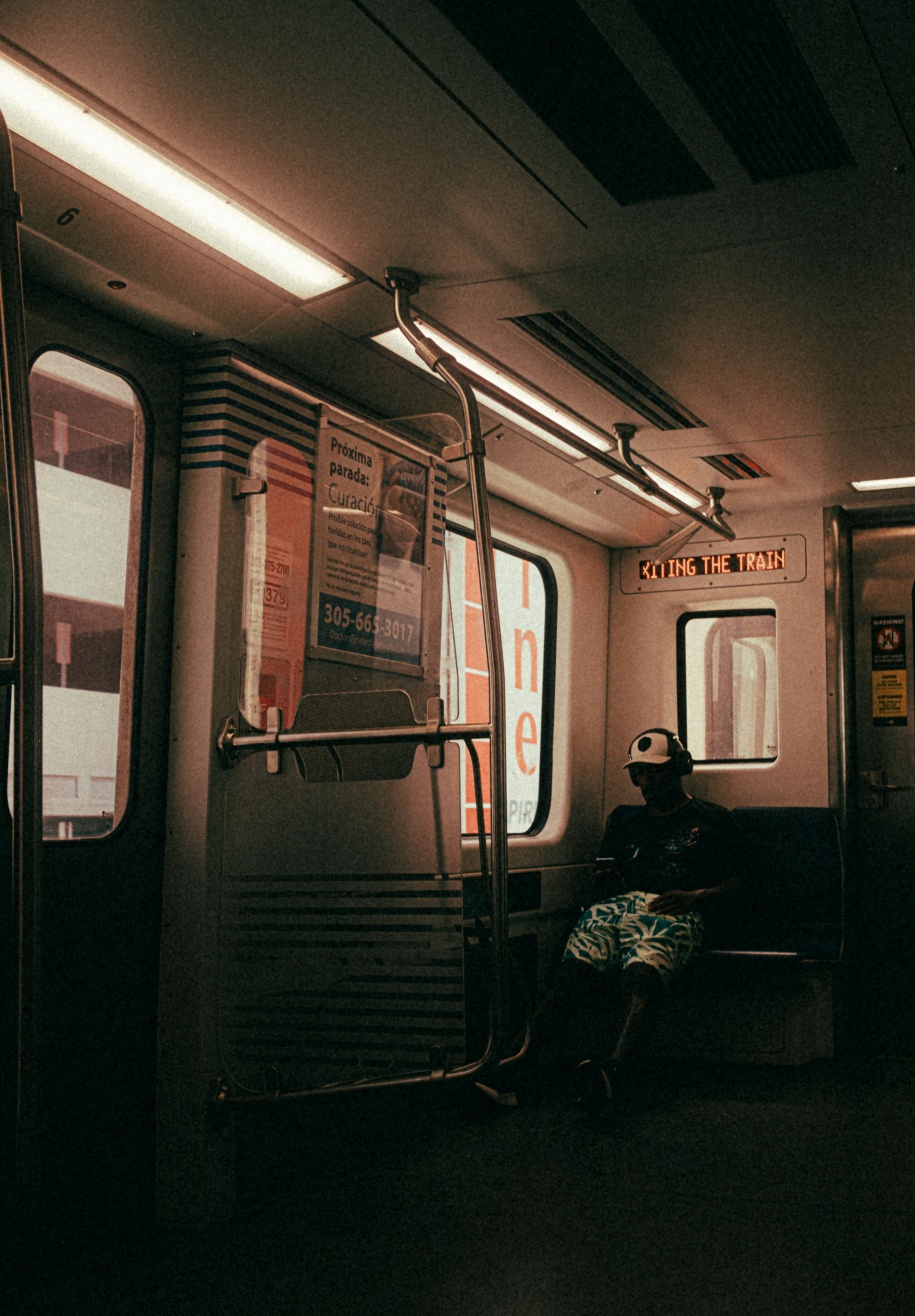A person sits alone inside a subway car.