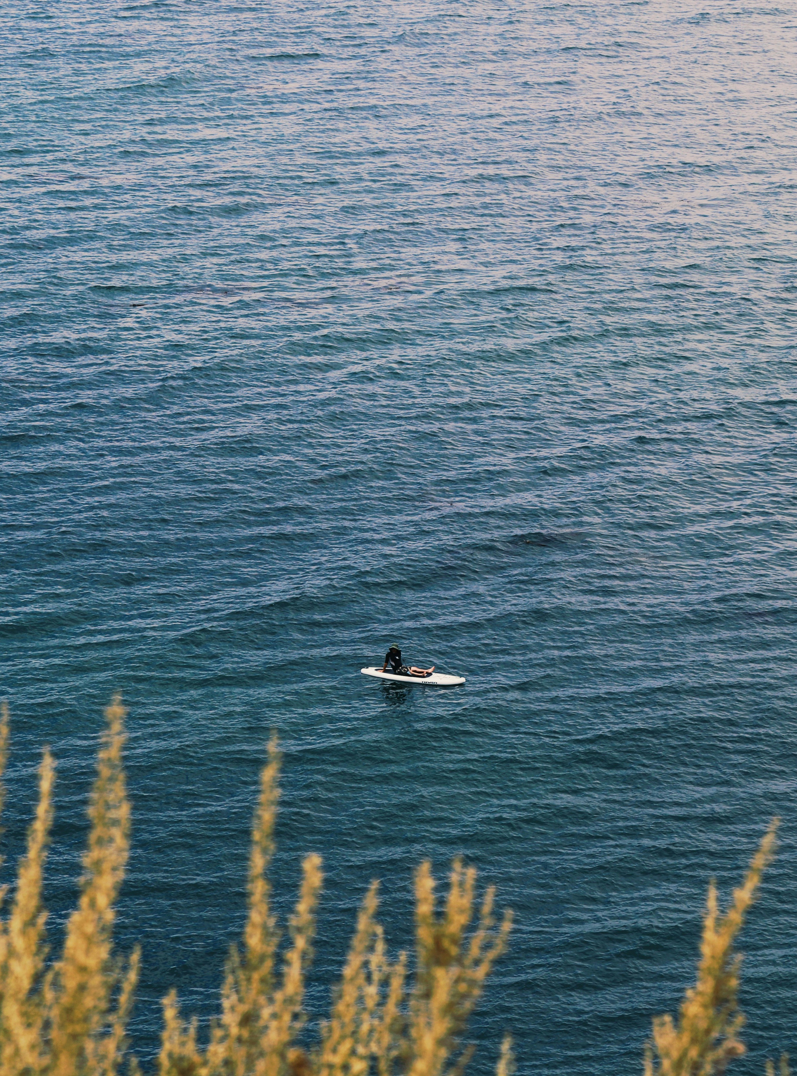 A person paddleboards on the calm ocean.