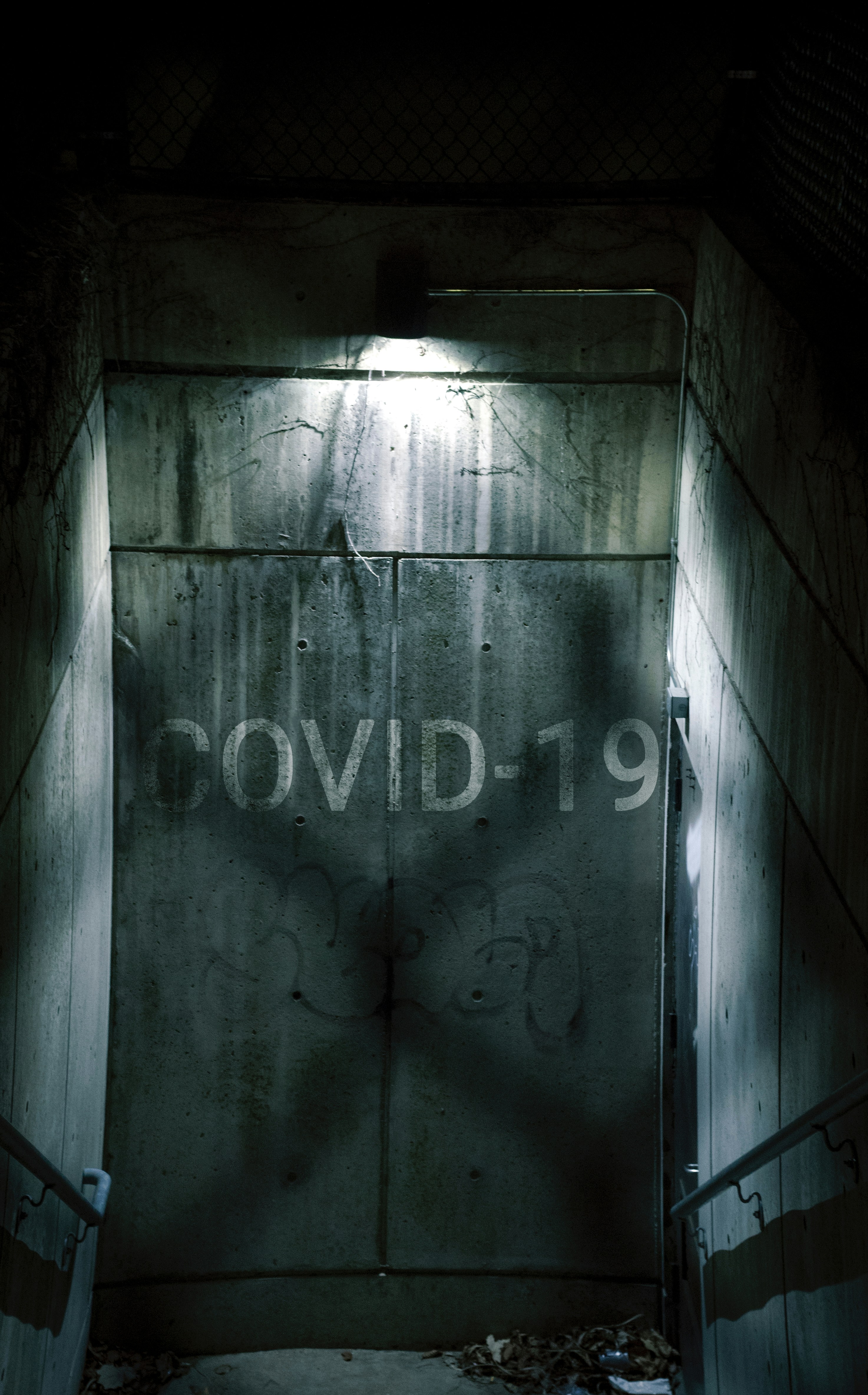 End of the Hall: COVID-19 Graffiti Framing a Dim Stairwell