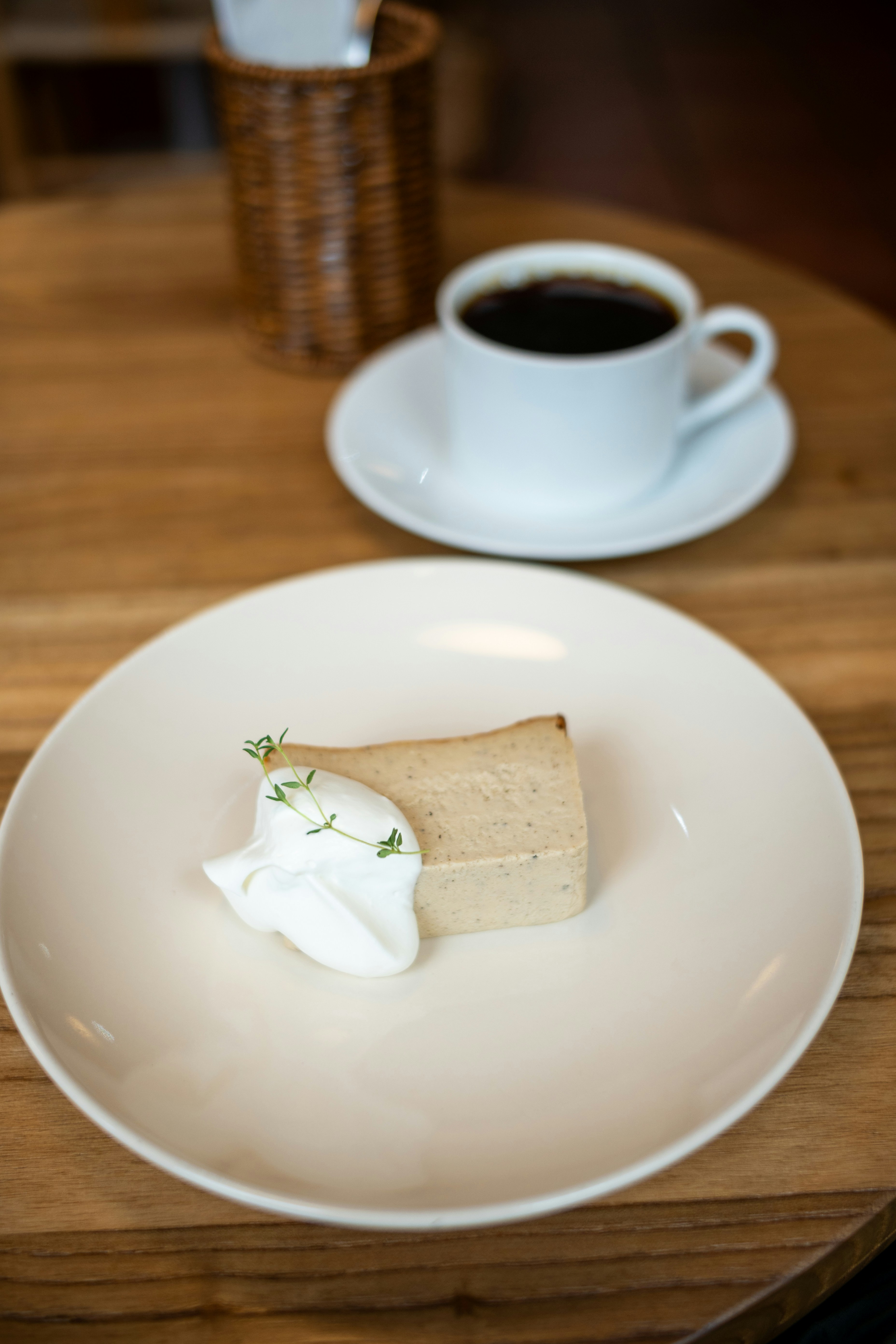 Cheesecake and coffee sit on a wooden table.