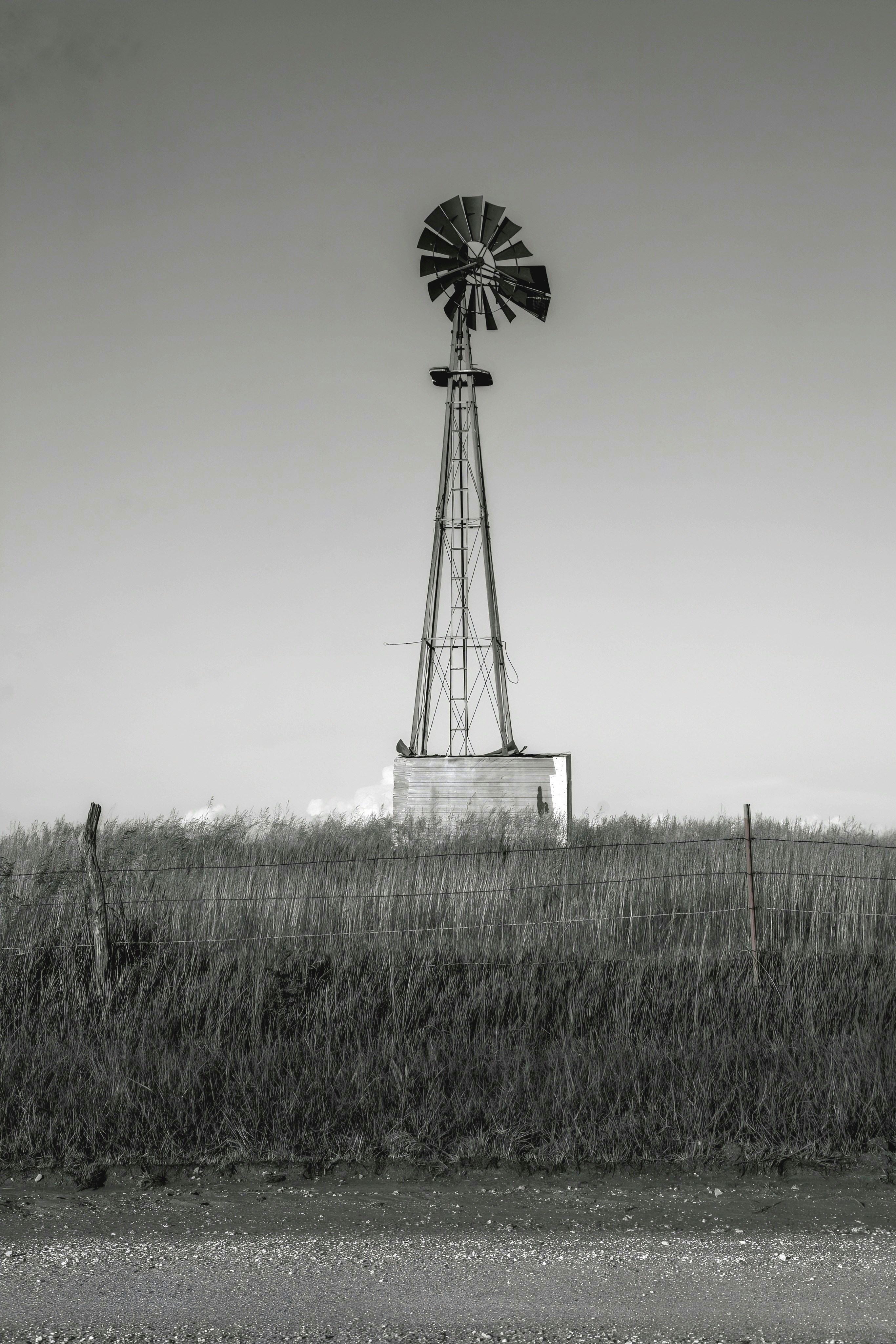 Feeling the wind's whispers through the windmill. | A windmill stands tall over grassy plains.