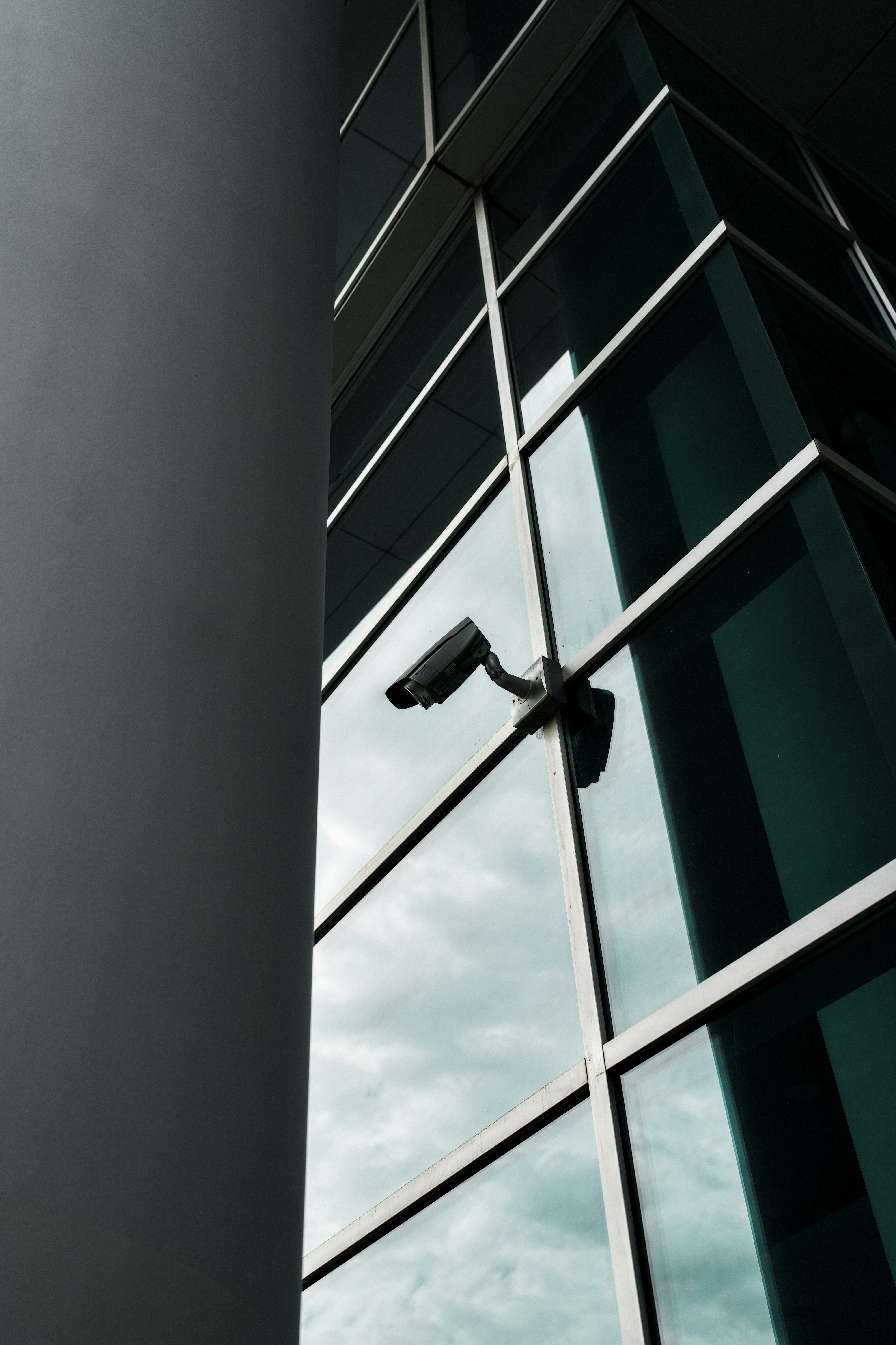 A security camera is mounted on a modern building.