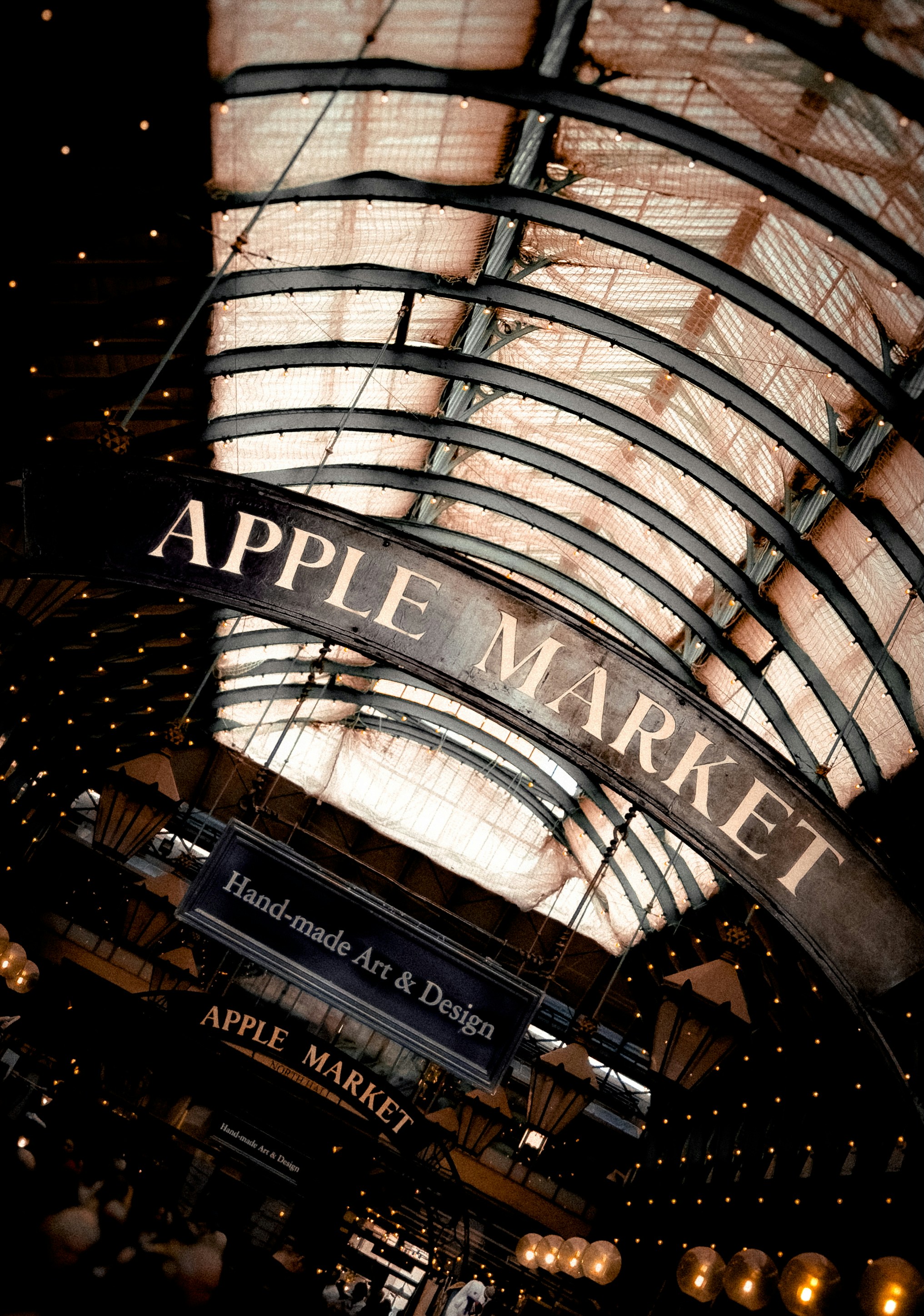 Elegant archway sign at Apple Market showcasing handmade art and design, framed by a beautifully lit ceiling.