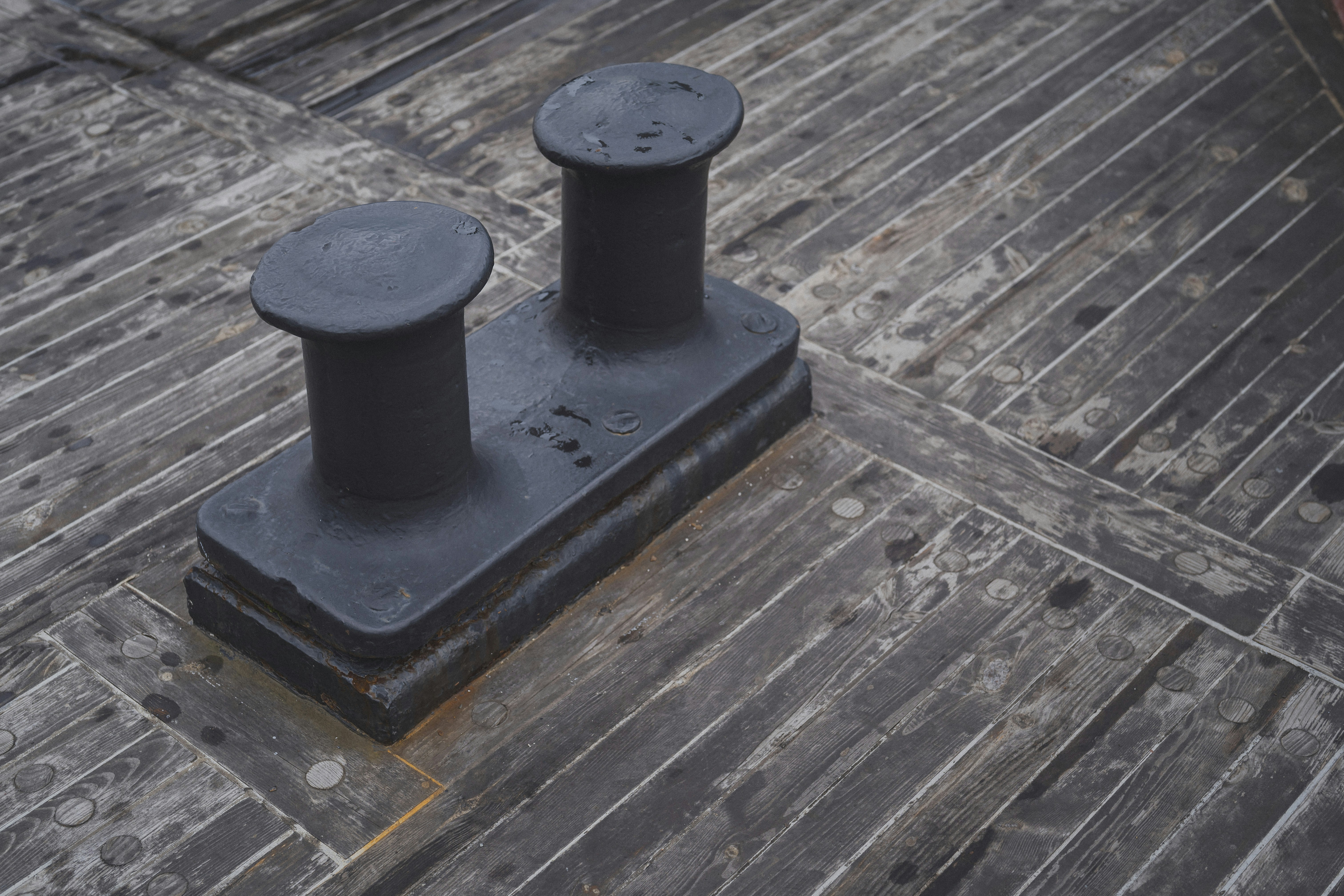 Weathered mooring cleats resting on a weathered wooden dock, showcasing the passage of time and maritime history.