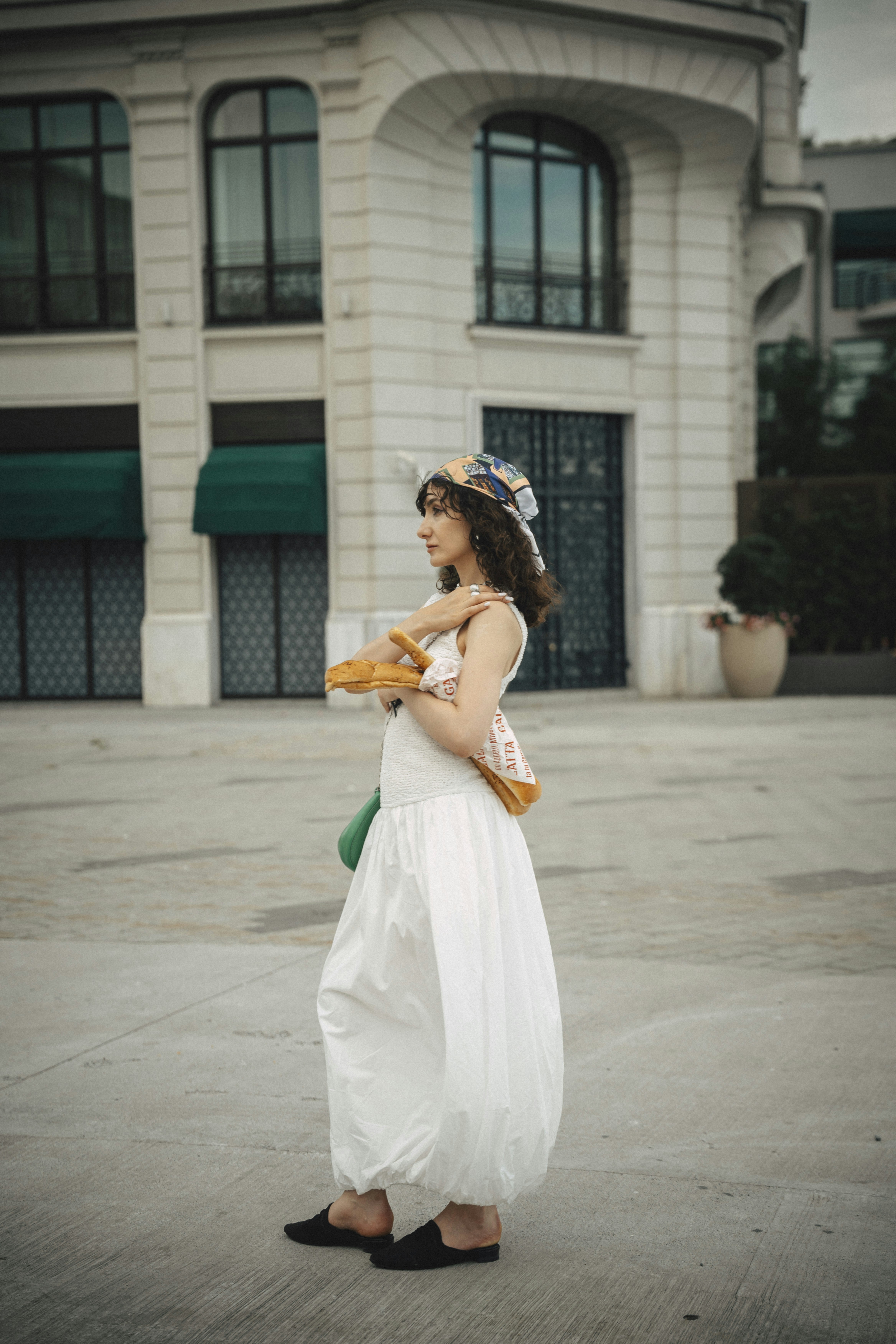 Woman stands elegantly, posing near a building.