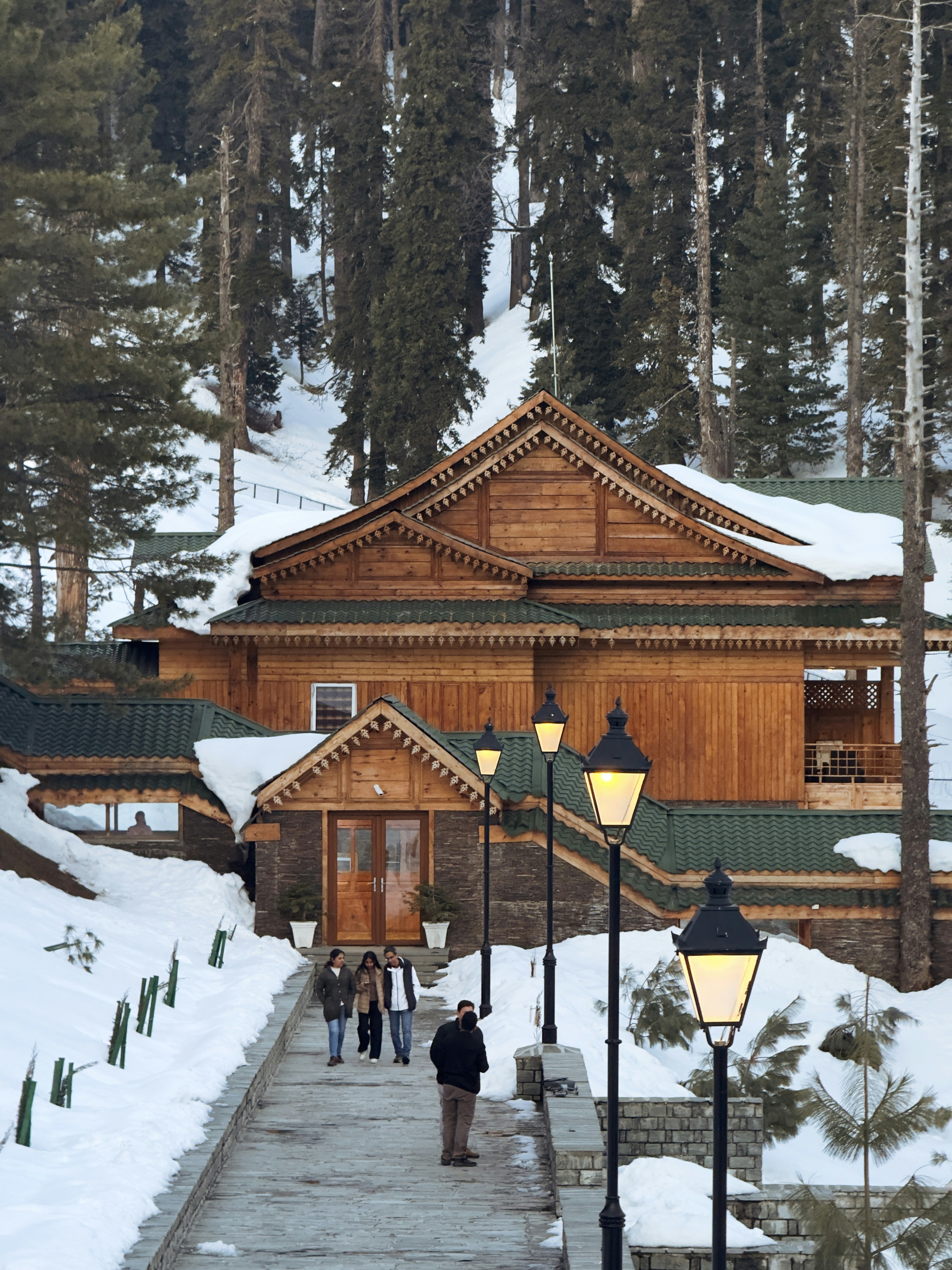 Wooden building and snowy path in a forest.