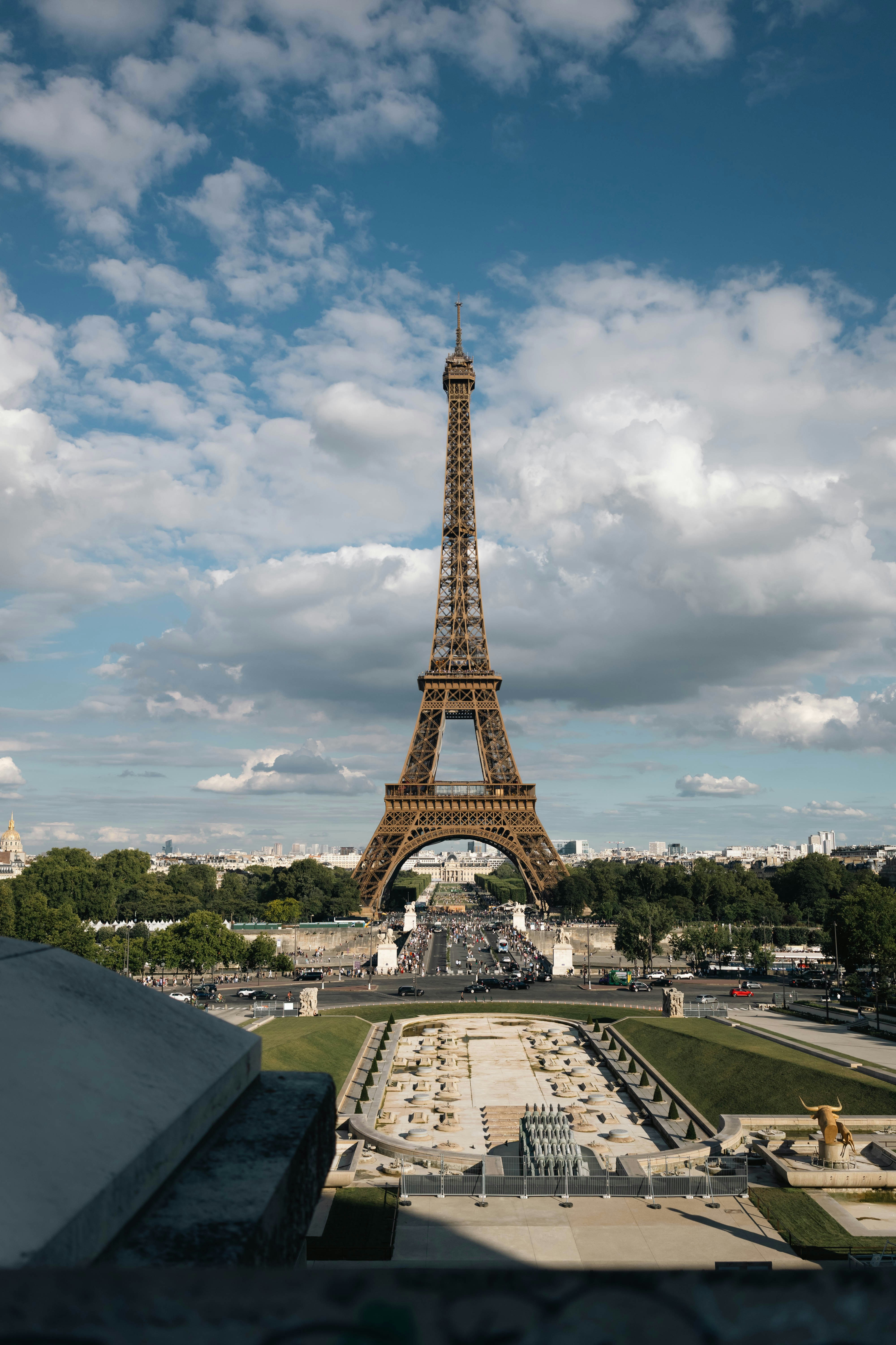 Eiffel Tower majestically rises above the bustling cityscape, framed by a vibrant sky and greenery below.