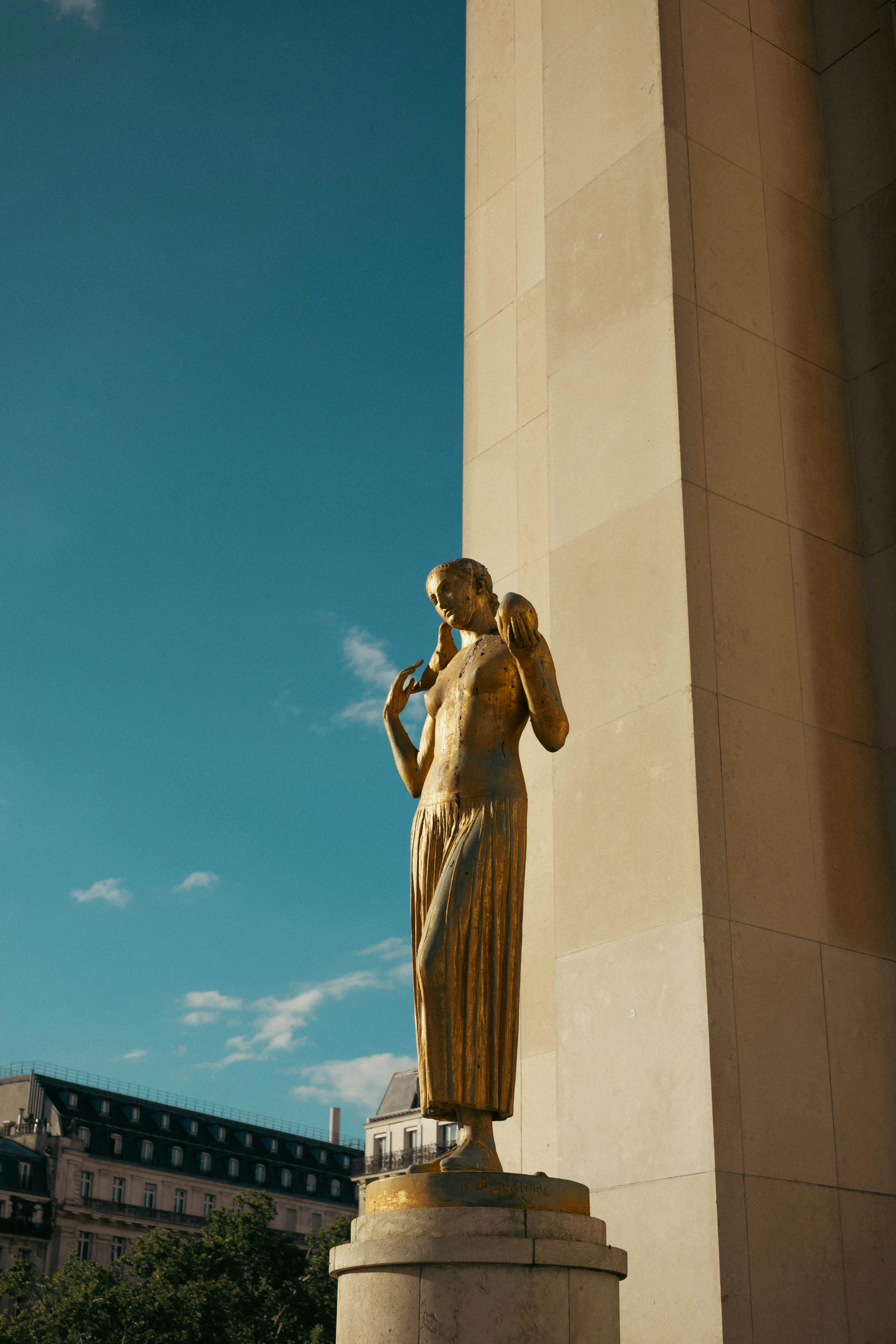 Bronze Figure at the Foot of a Monumental Column Under a Cerulean Sky