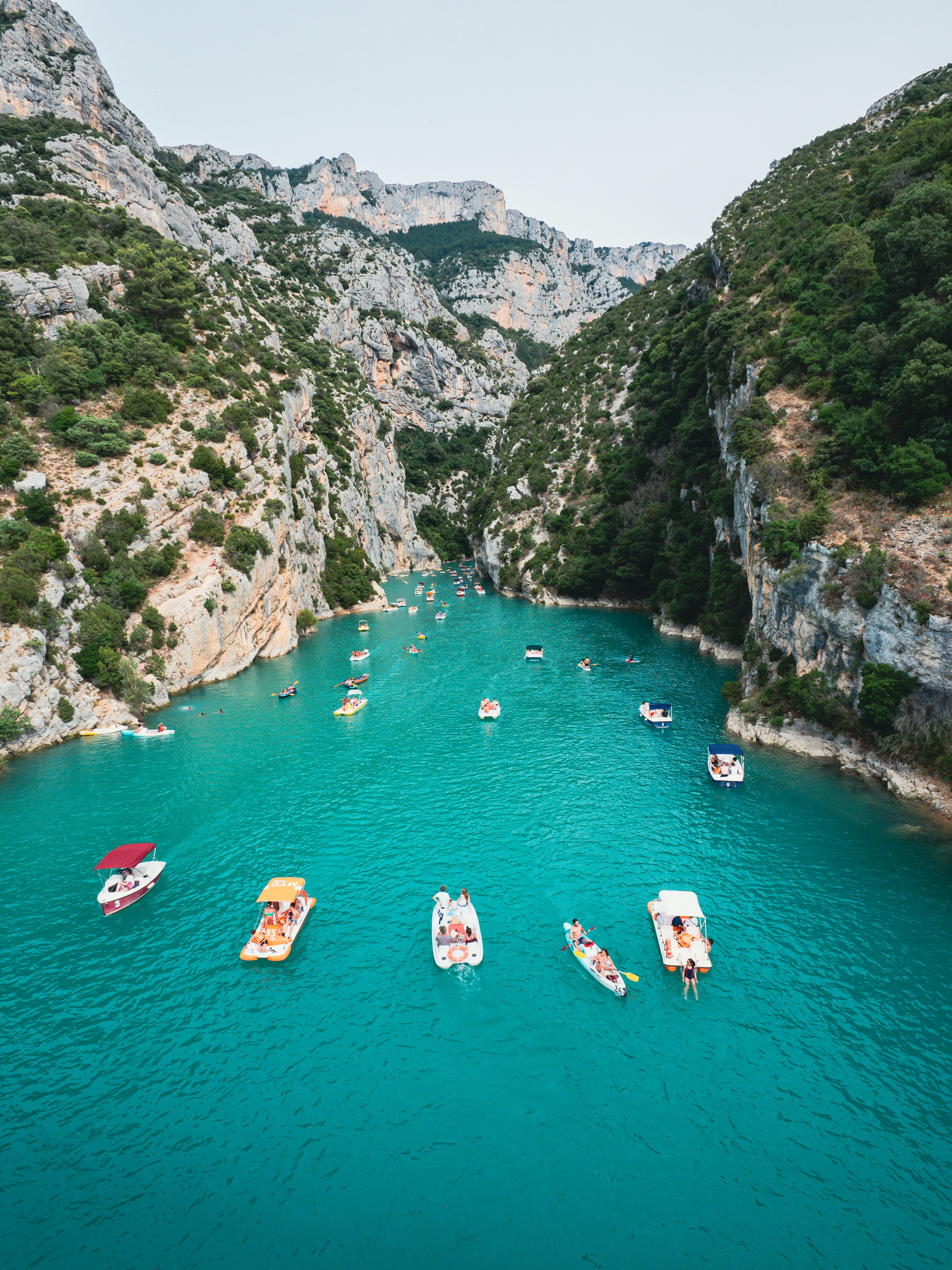 Boats float on a turquoise lake within mountains.