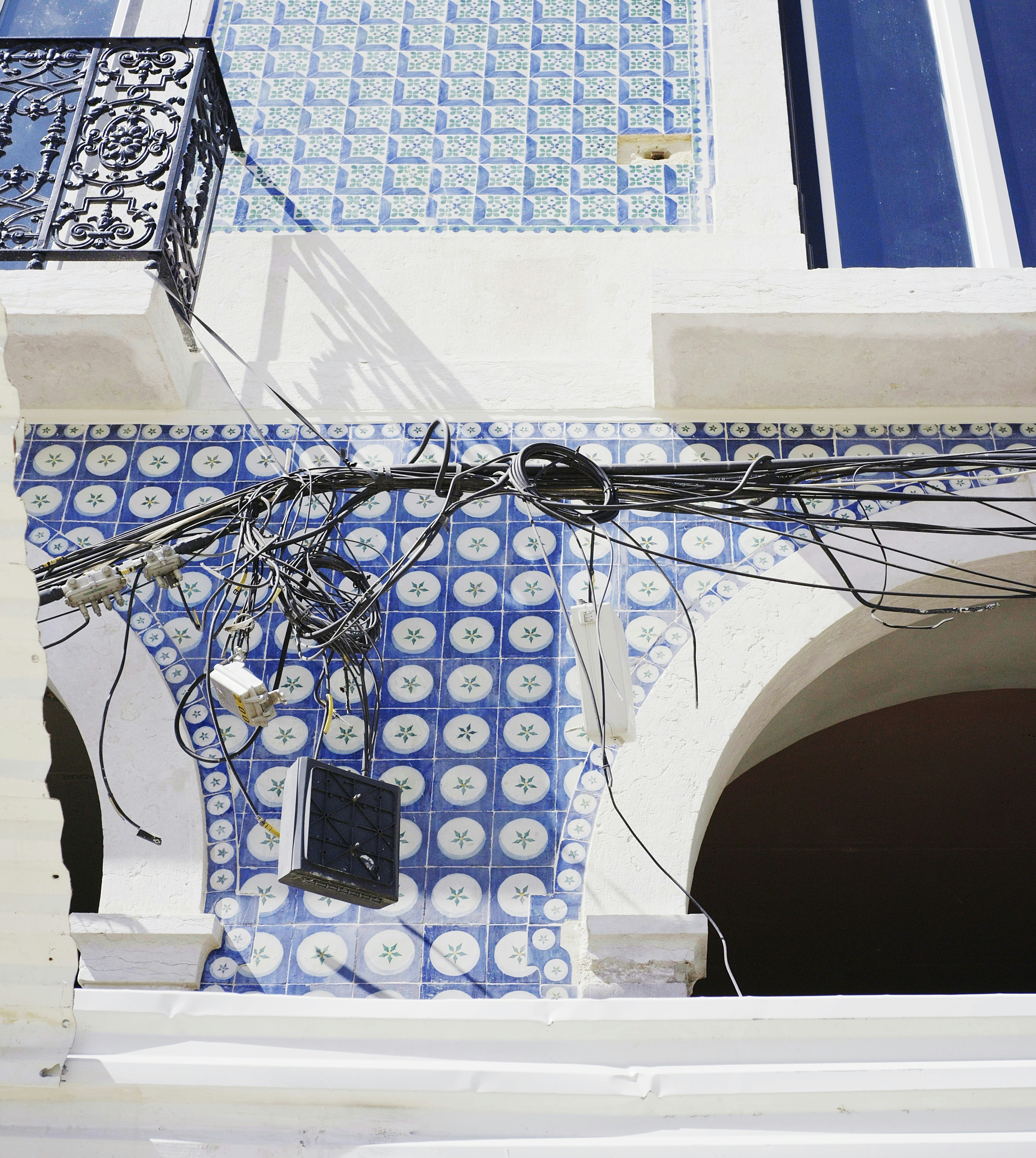 A building facade adorned with blue tiles and cables.