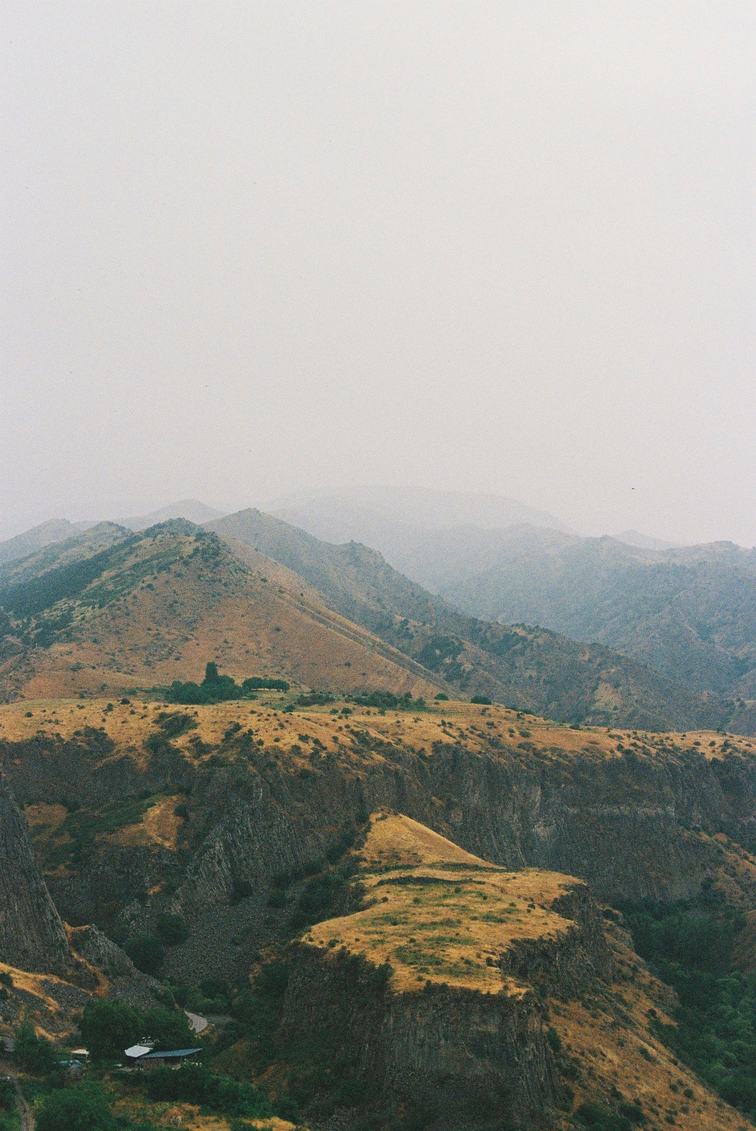 Hilly landscape under a hazy, overcast sky.