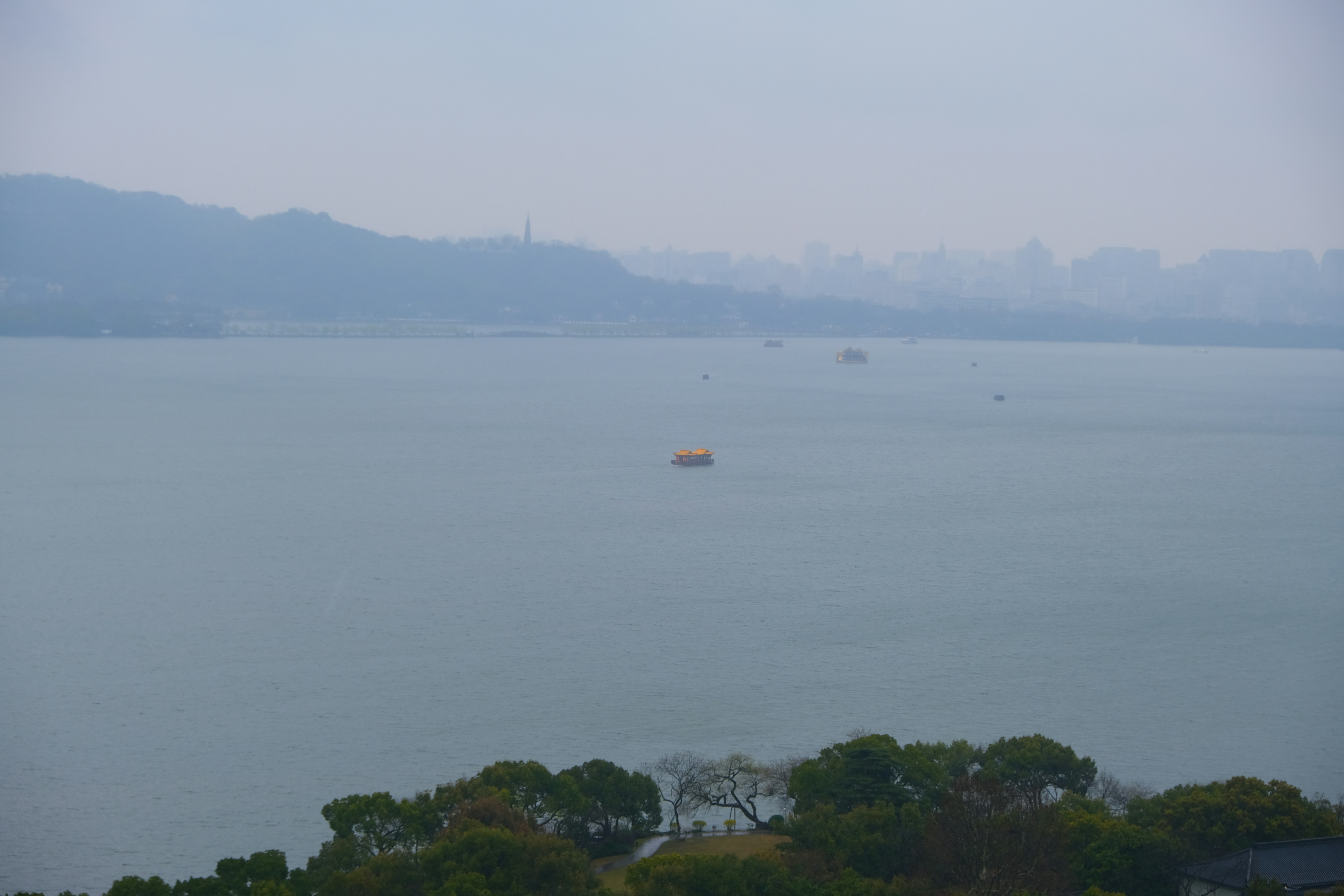 West Lake, Hangzhou. | A misty lake with distant boats.