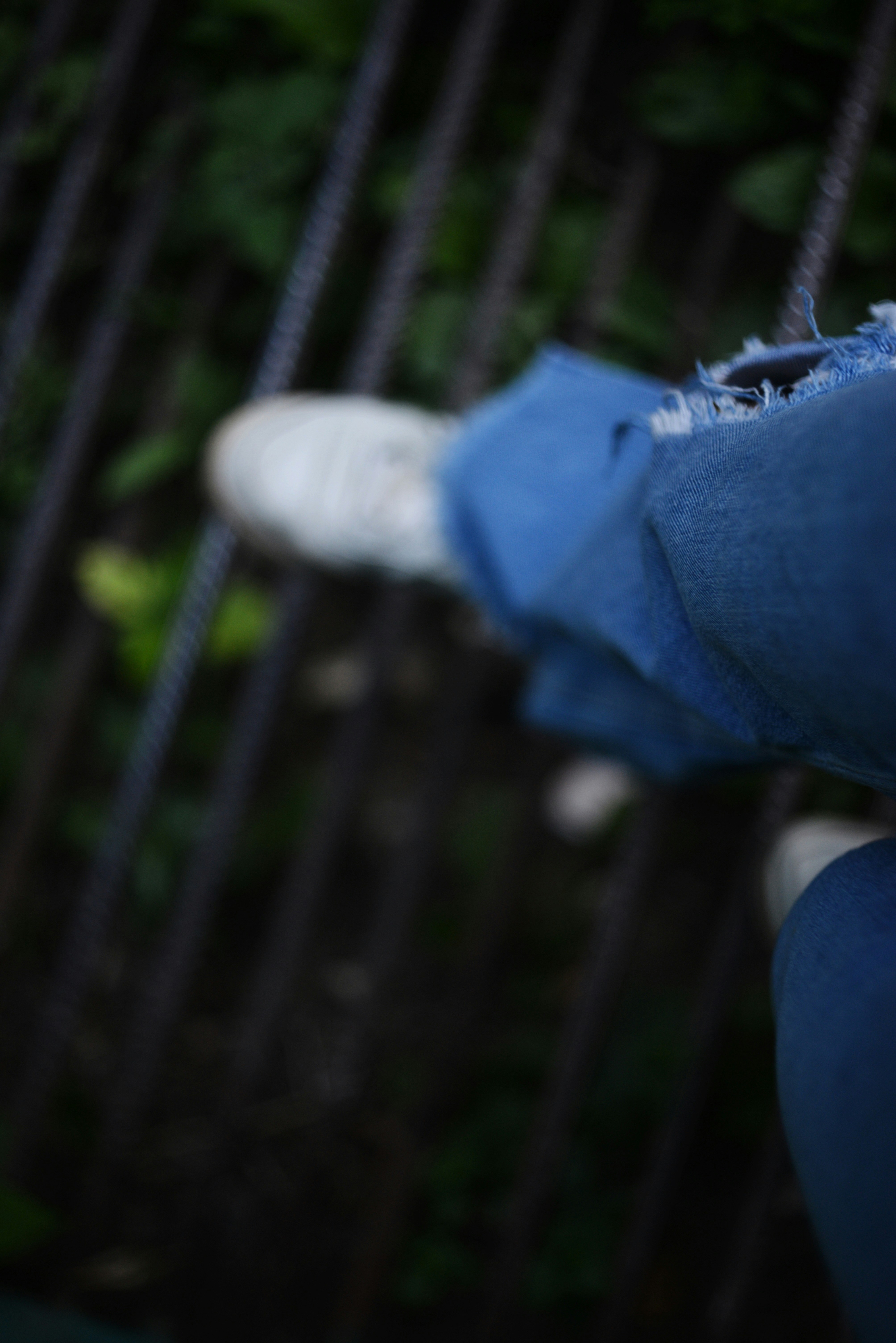 A close-up of a foot stepping on a metal grate, surrounded by lush greenery, highlighting the contrast between urban elements and nature.