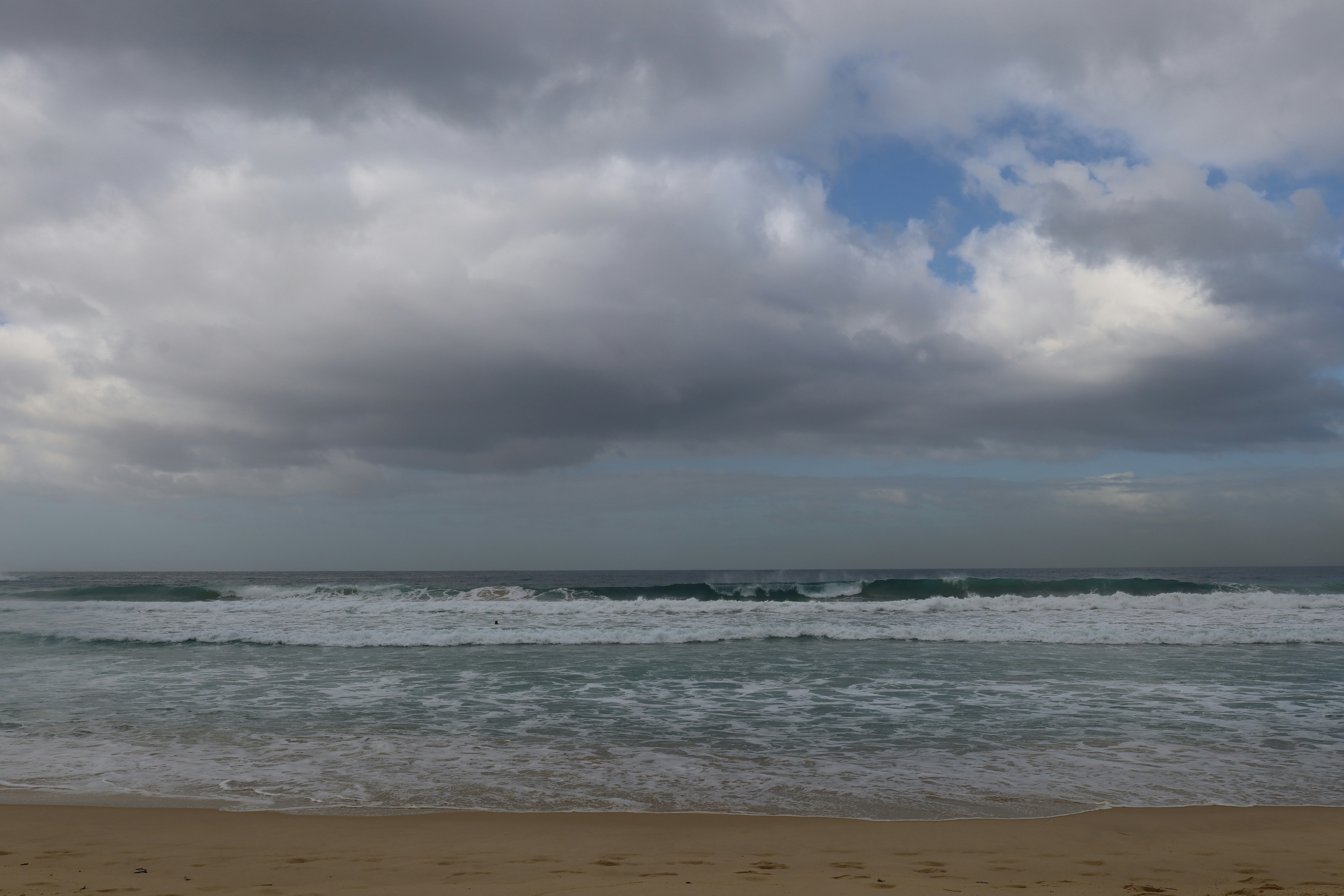 Overcast skies and ocean waves create a serene beach scene.