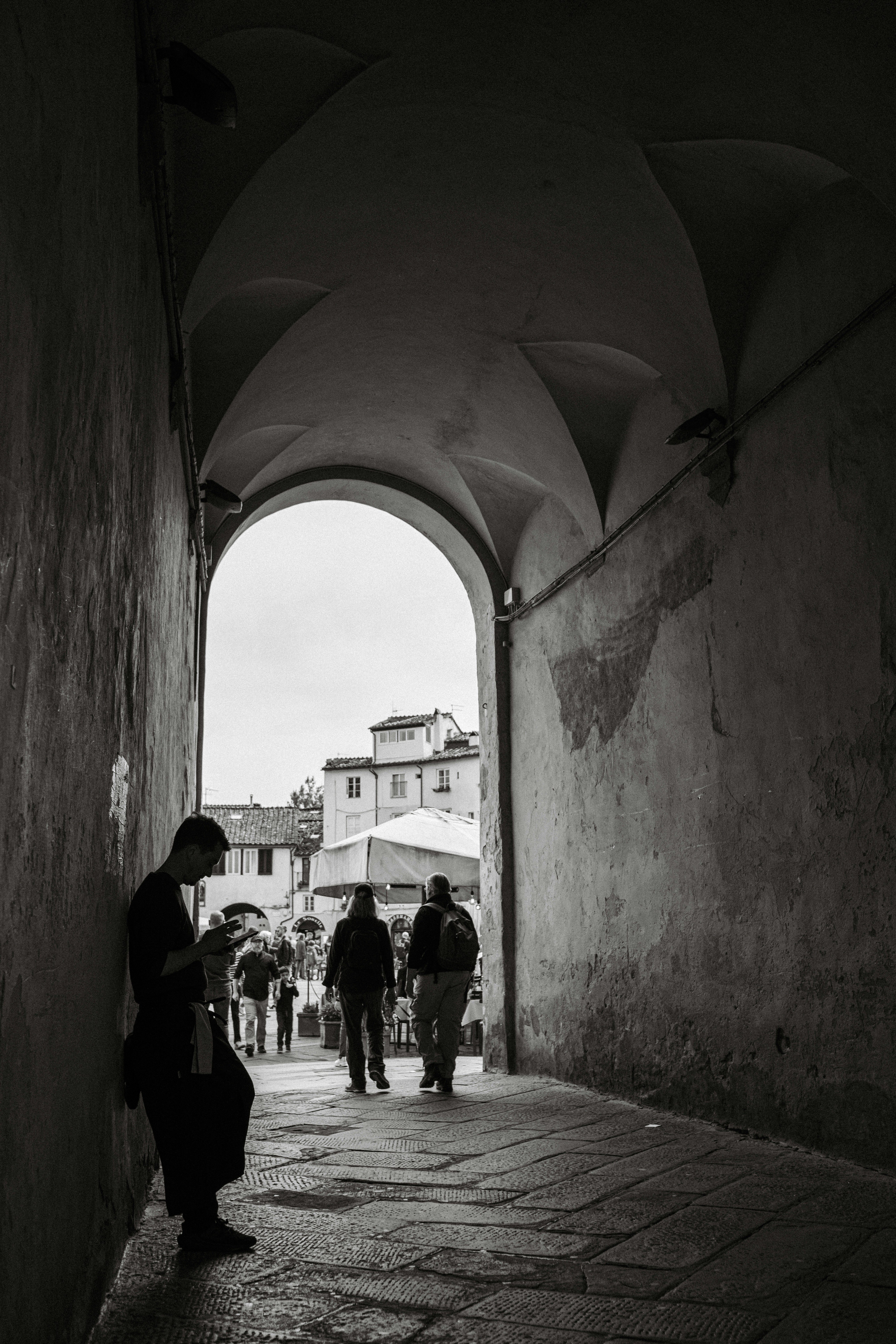 People walk through an arched alleyway.