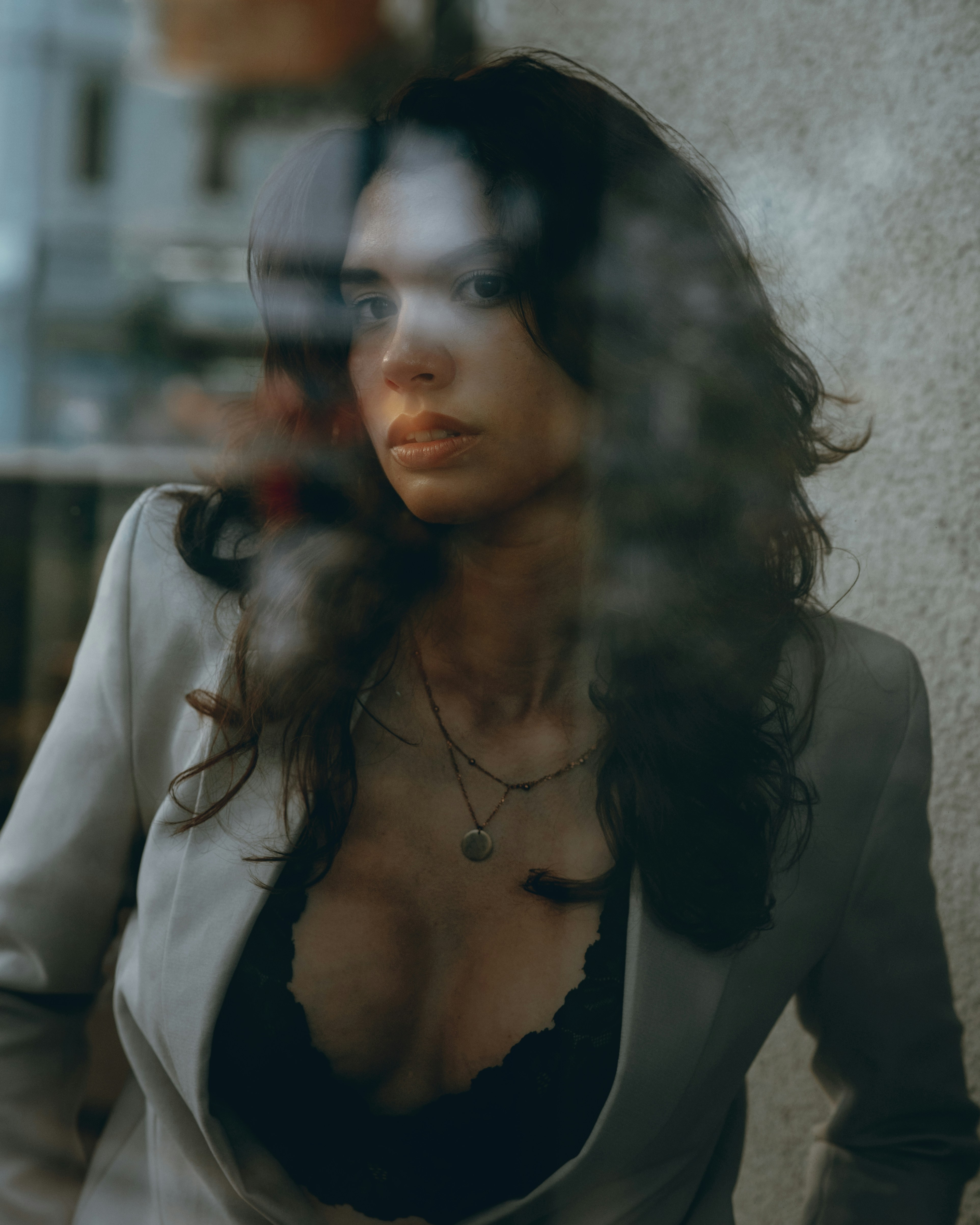 A woman looks pensively through a window.