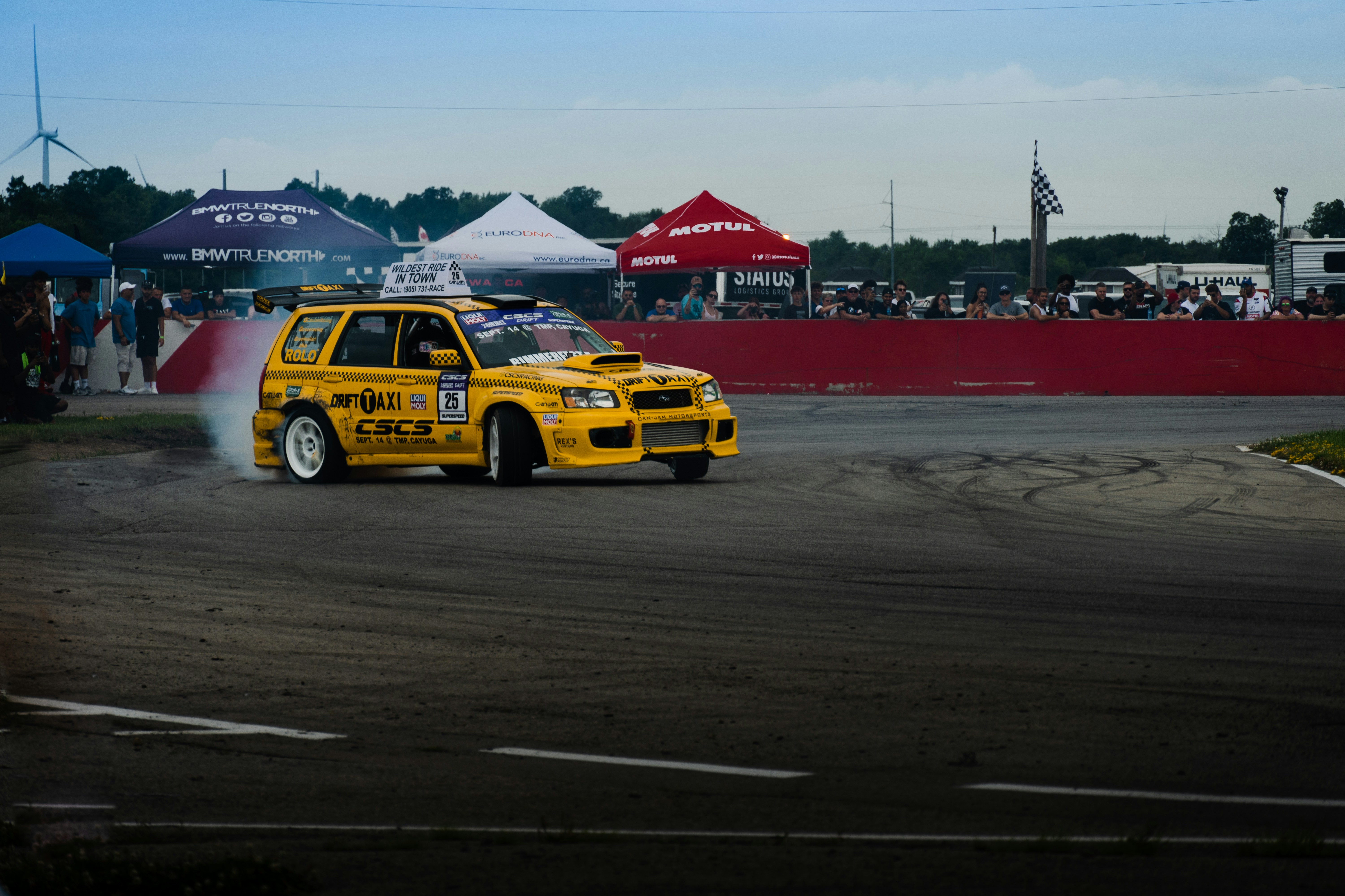 A yellow car drifts on a racetrack.