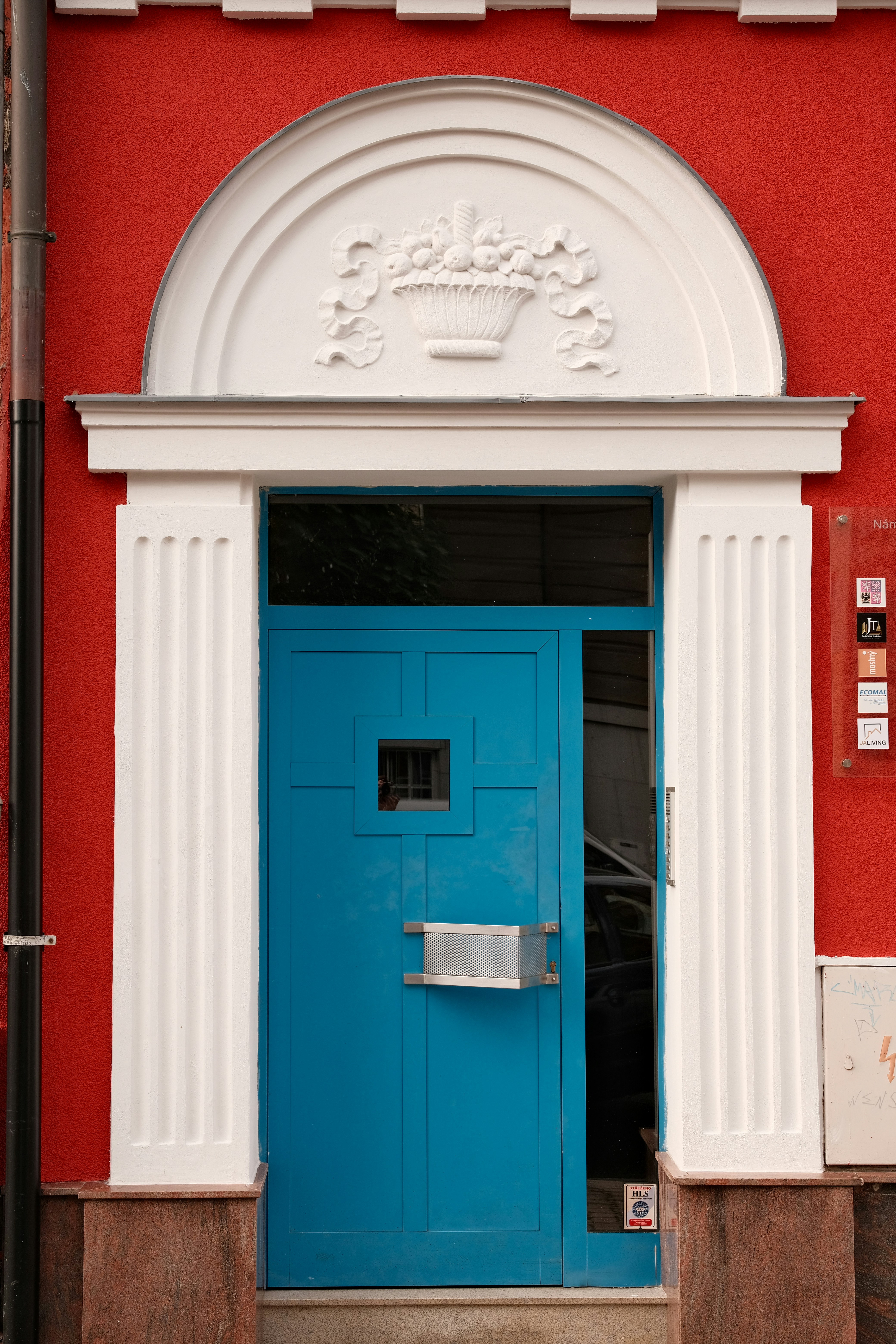 Doorway with blue entrance and white details | A blue door is framed against a red wall.