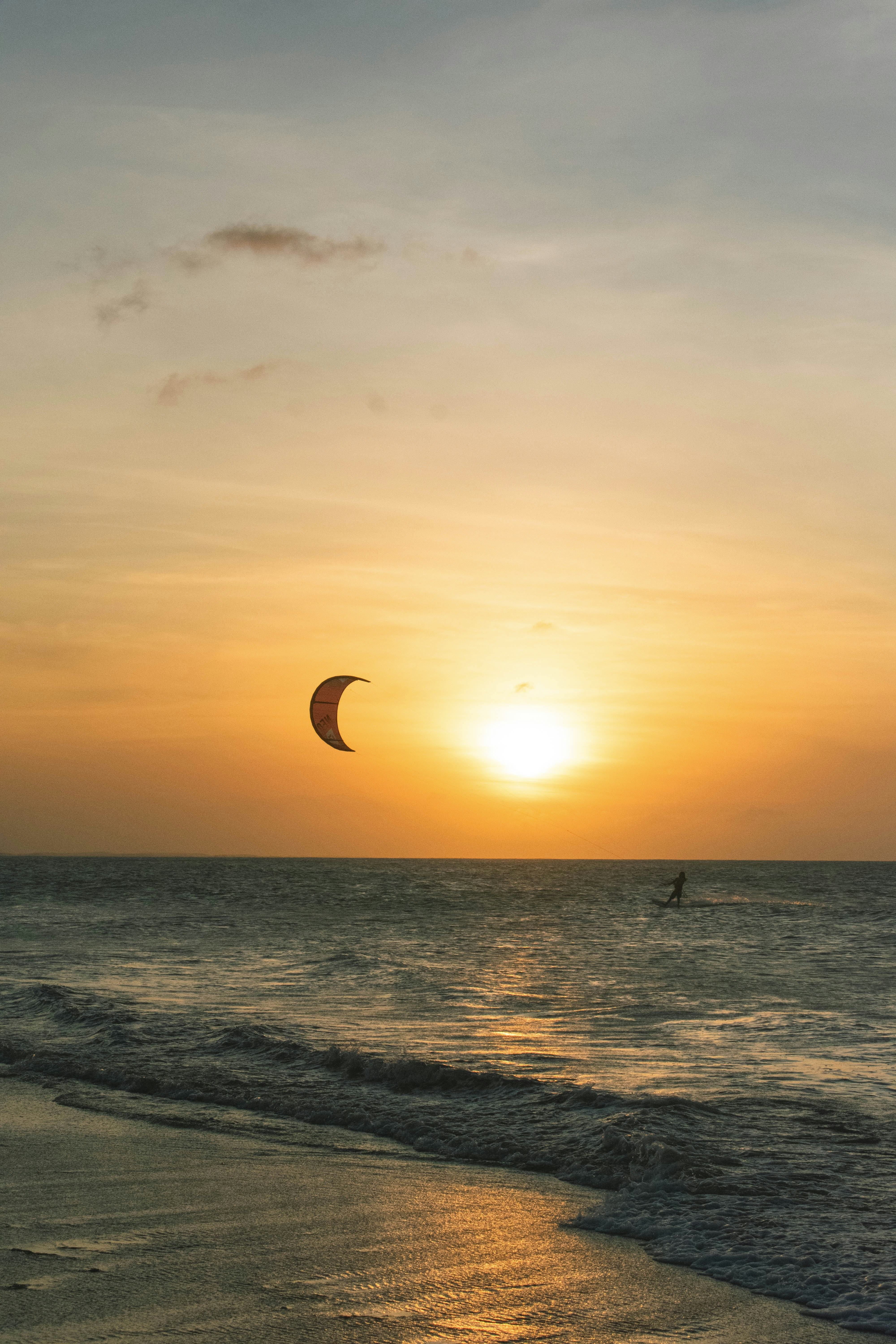 Kite surfer enjoys a beautiful sunset on the ocean.